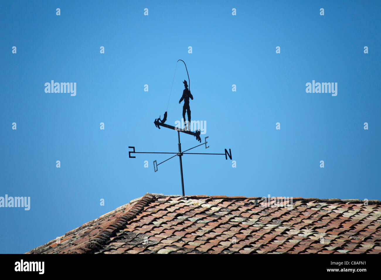 Weather vane (weathercock) of fishing man on tiled roof, blue sky Stock ...