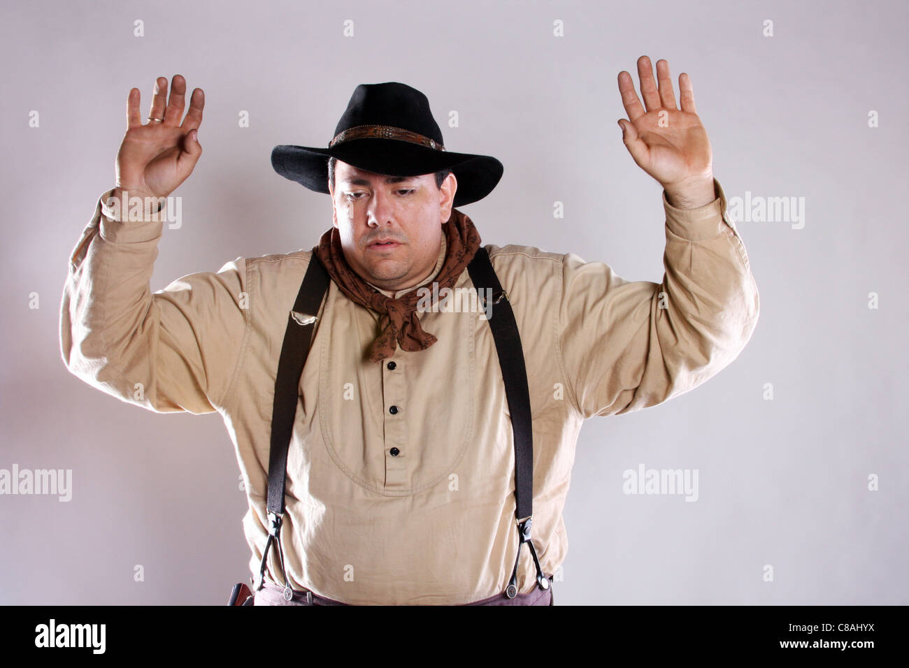 A cowboy raising his hands under arrest looking down Stock Photo - Alamy