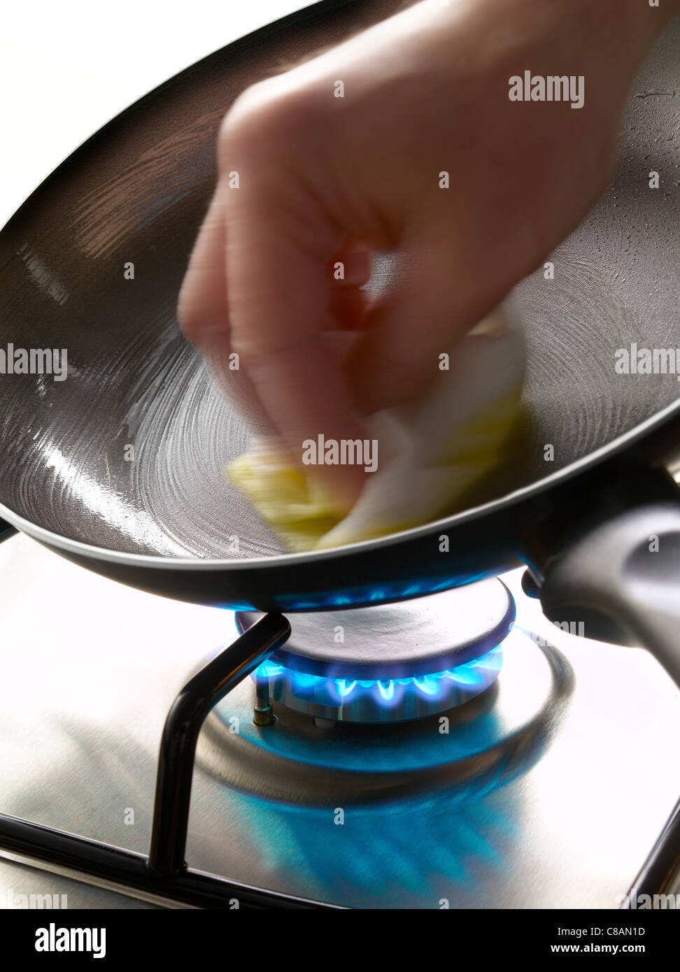Greasing a frying pan on the gas cooker Stock Photo - Alamy