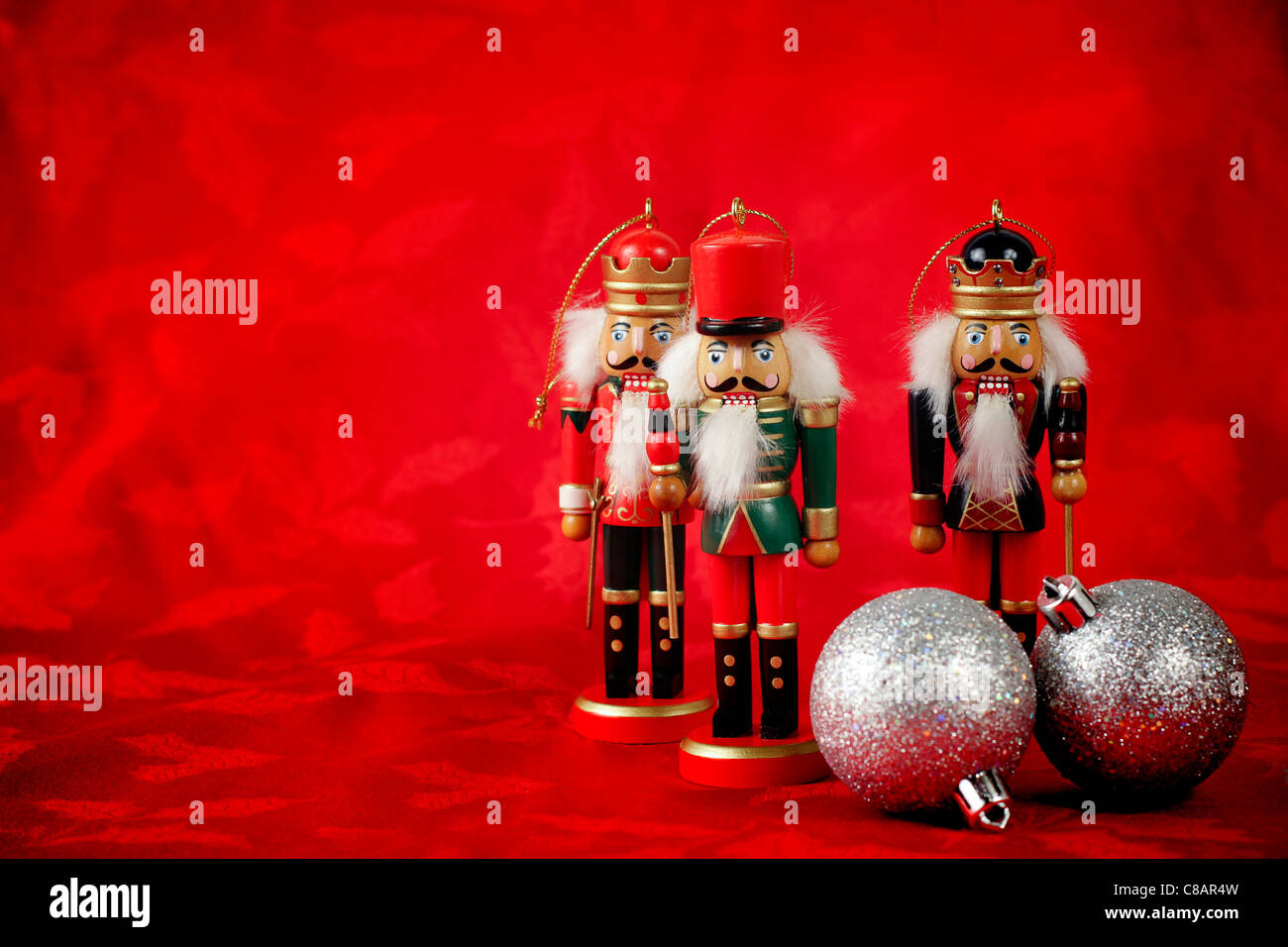 Three nutcrackers stand on red Christmas background with ornaments ...