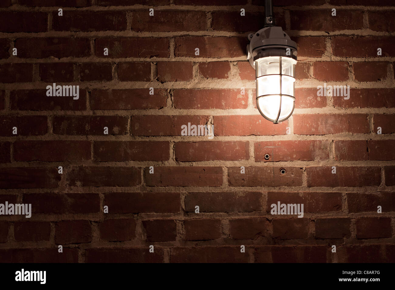 Creepy light bulb on textured red brick wall Stock Photo - Alamy