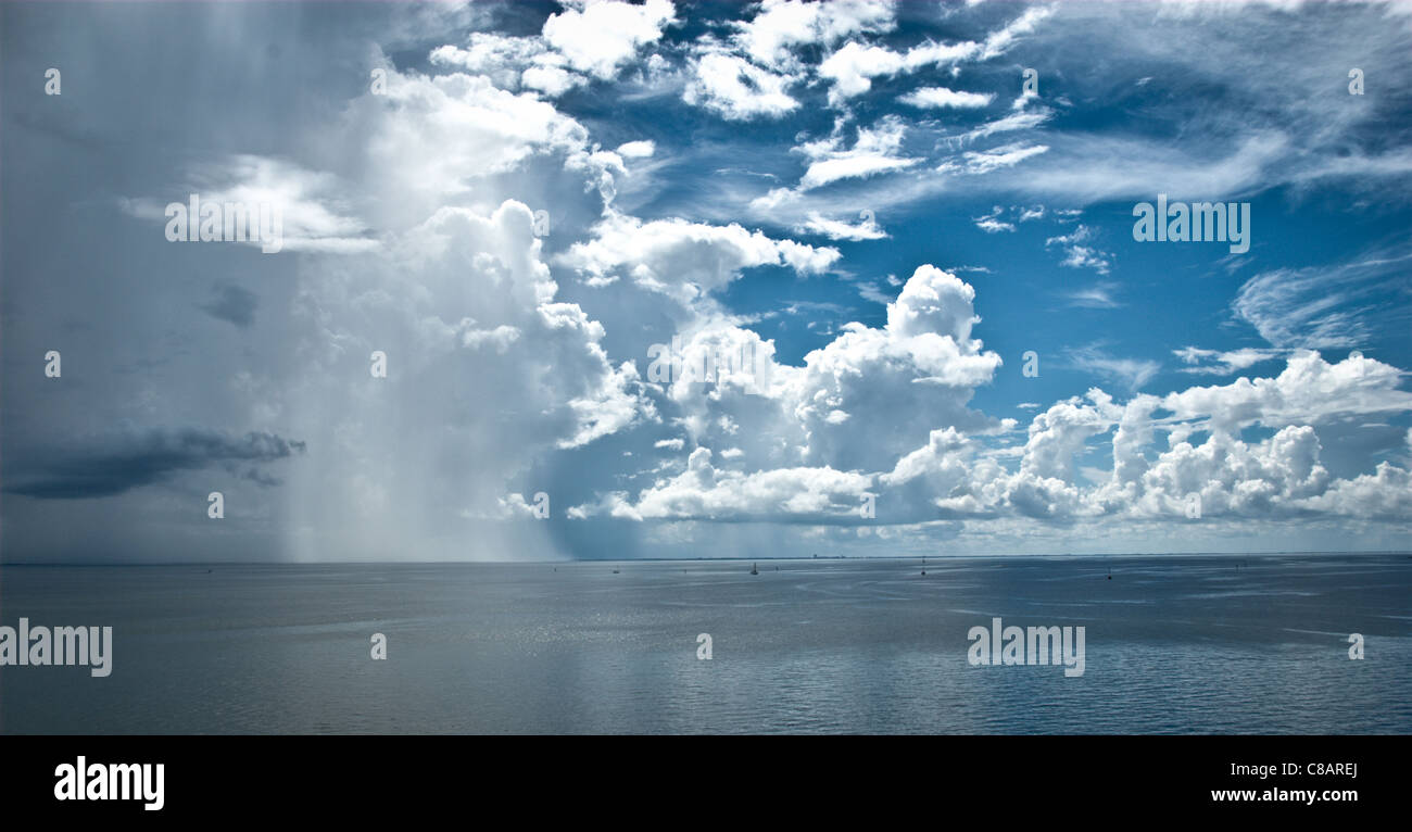Rain in the distance over the ocean, below vivid clouds Stock Photo - Alamy
