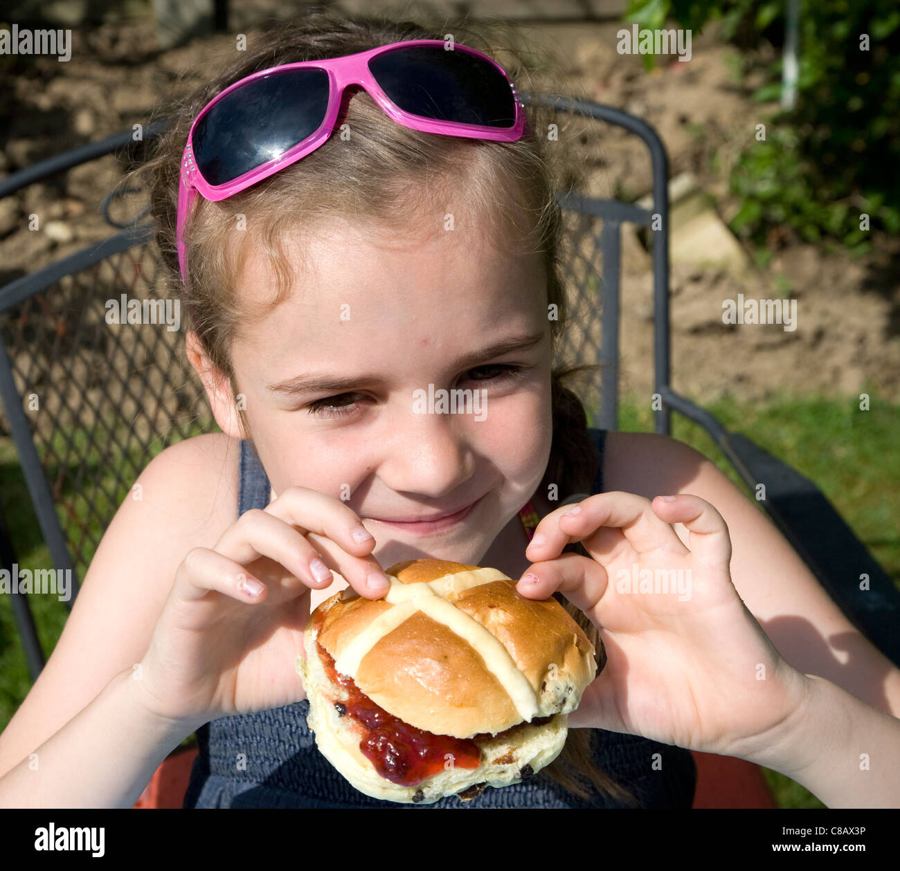 Girl eating Hot Cross Bun Stock Photo - Alamy