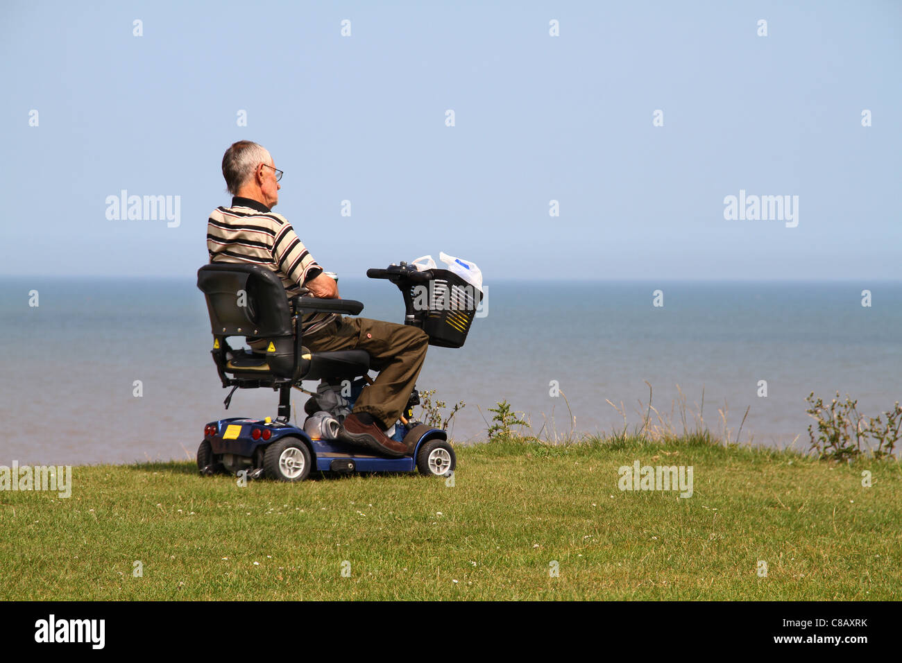 Man on motability bike on cliff top Stock Photo - Alamy