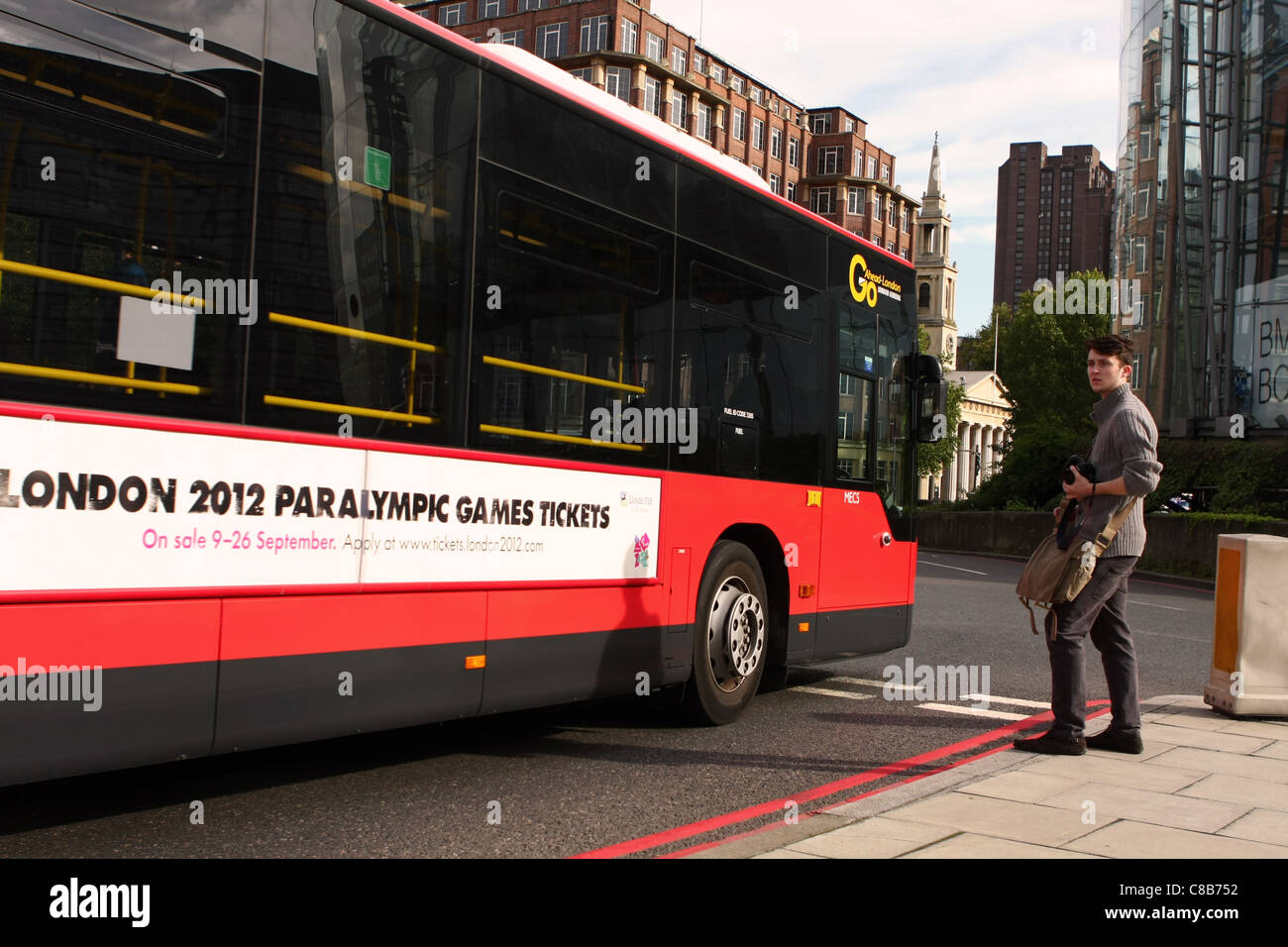 A single decker London bus waiting to enter a roundabout with a male ...