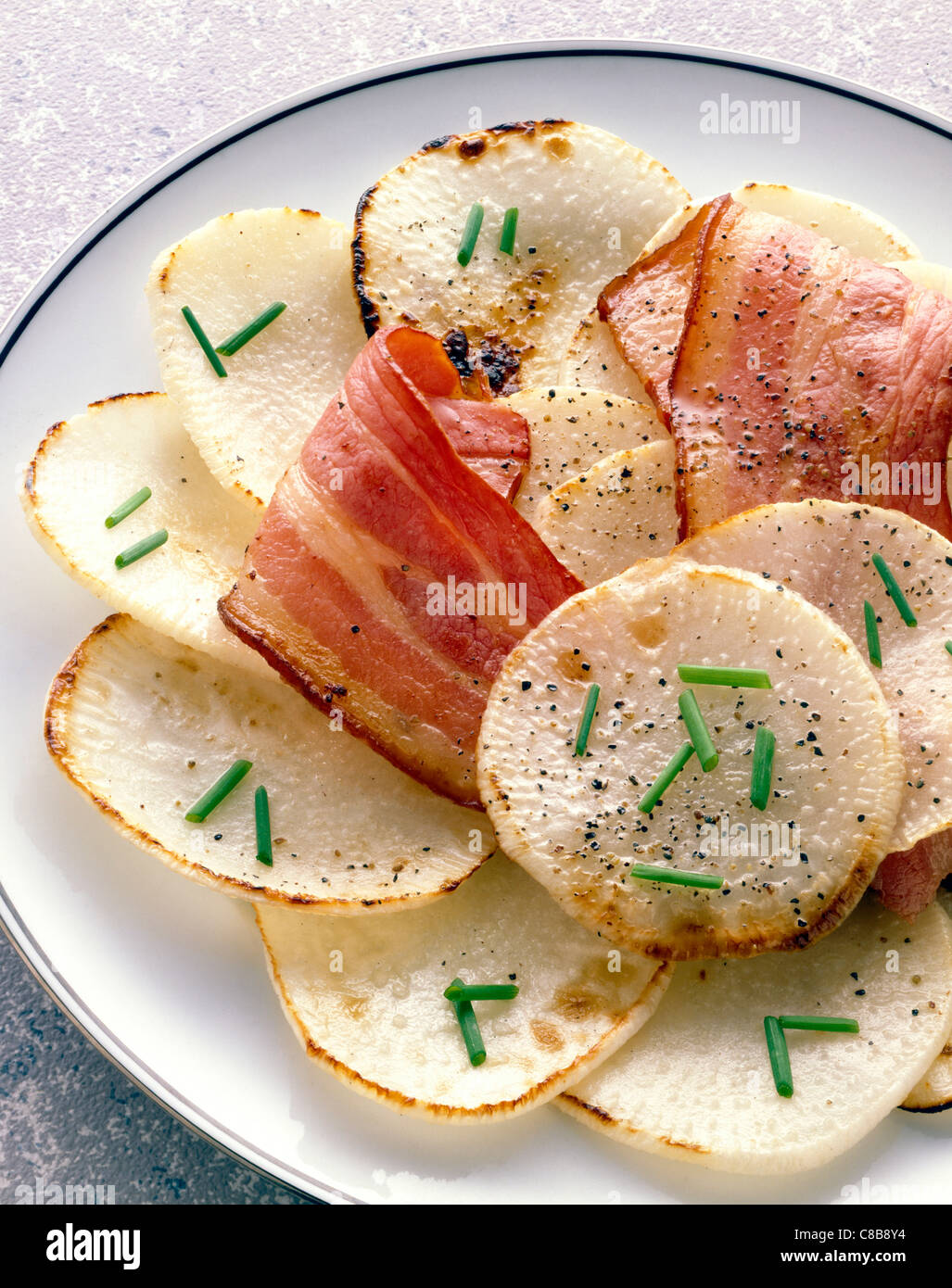Crispy discs of sautéed black radish with smoked bacon Stock Photo - Alamy
