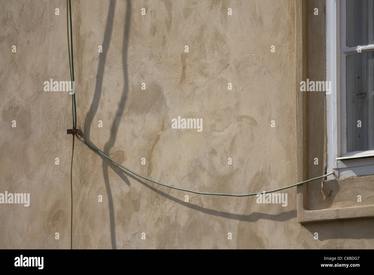A wall with a cord entering a window Stock Photo - Alamy