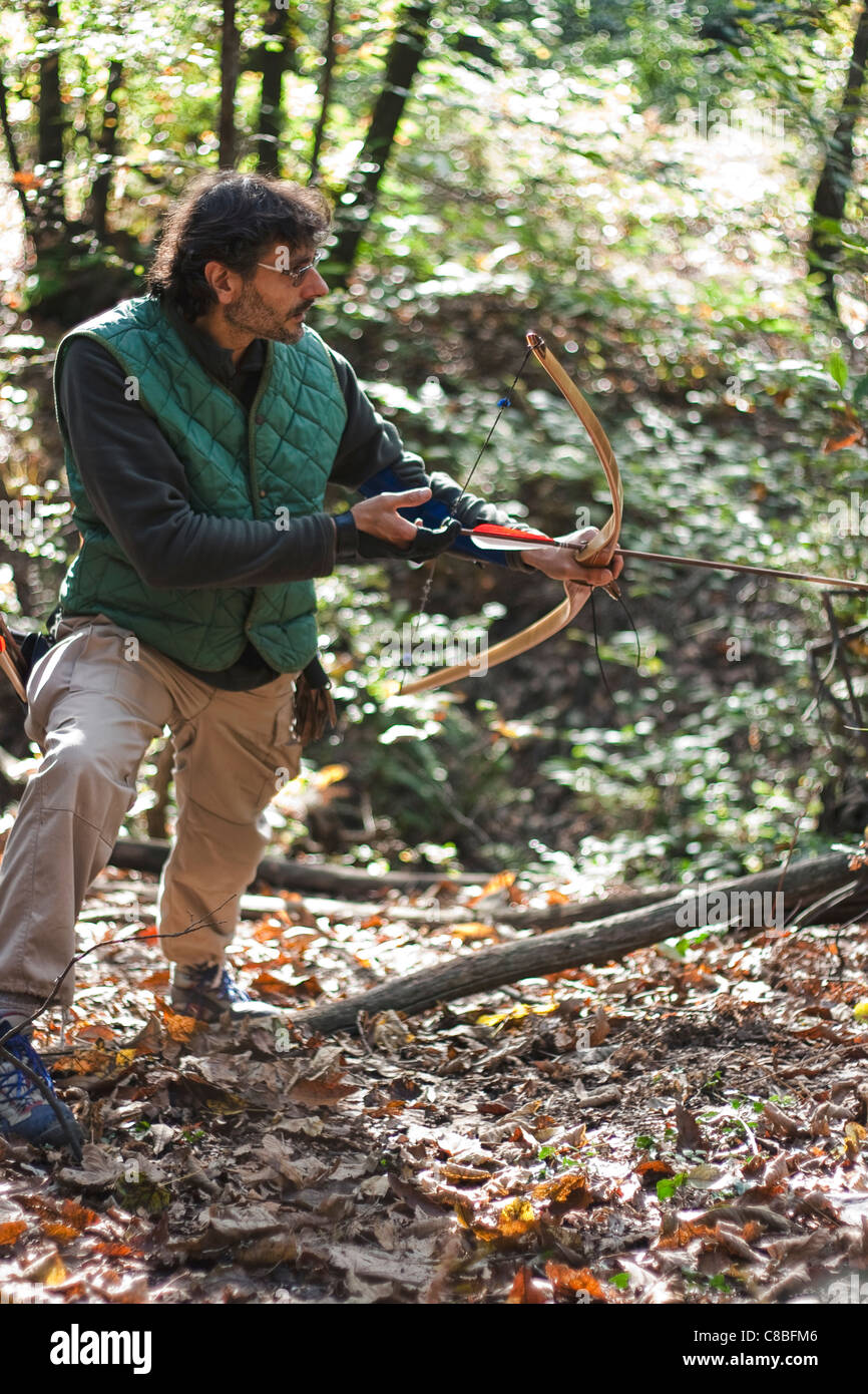 longbow man practicing archery in a forest Stock Photo - Alamy