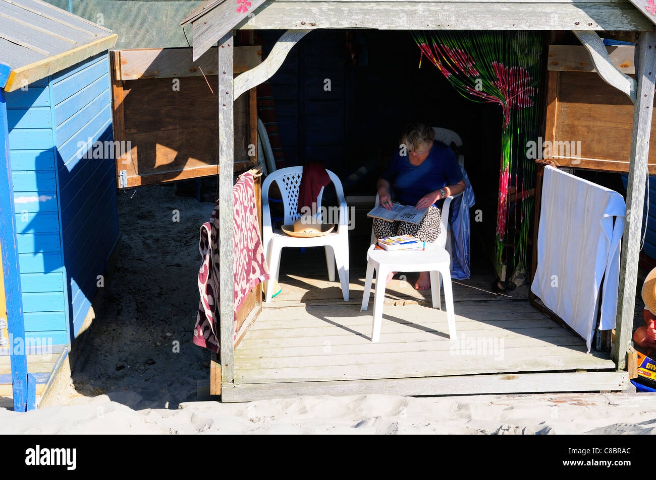 Woman reading in her beach hut and enjoying the unusually hot October ...