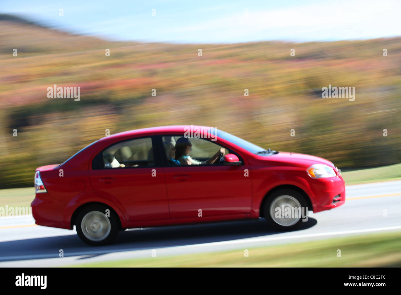 Red car speed through vibrant fall foliage on highway in Vermont Stock ...
