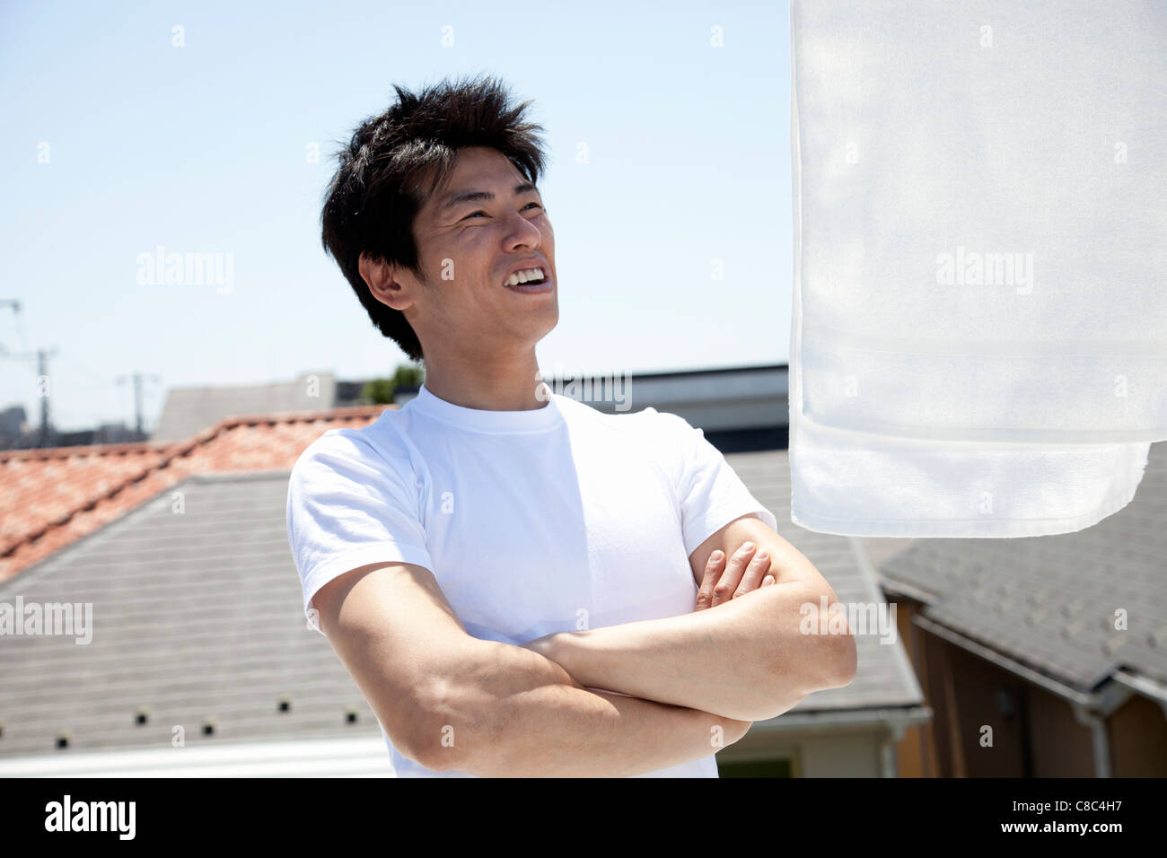 Mid adult man crossing arms and looking hanged laundry Stock Photo - Alamy
