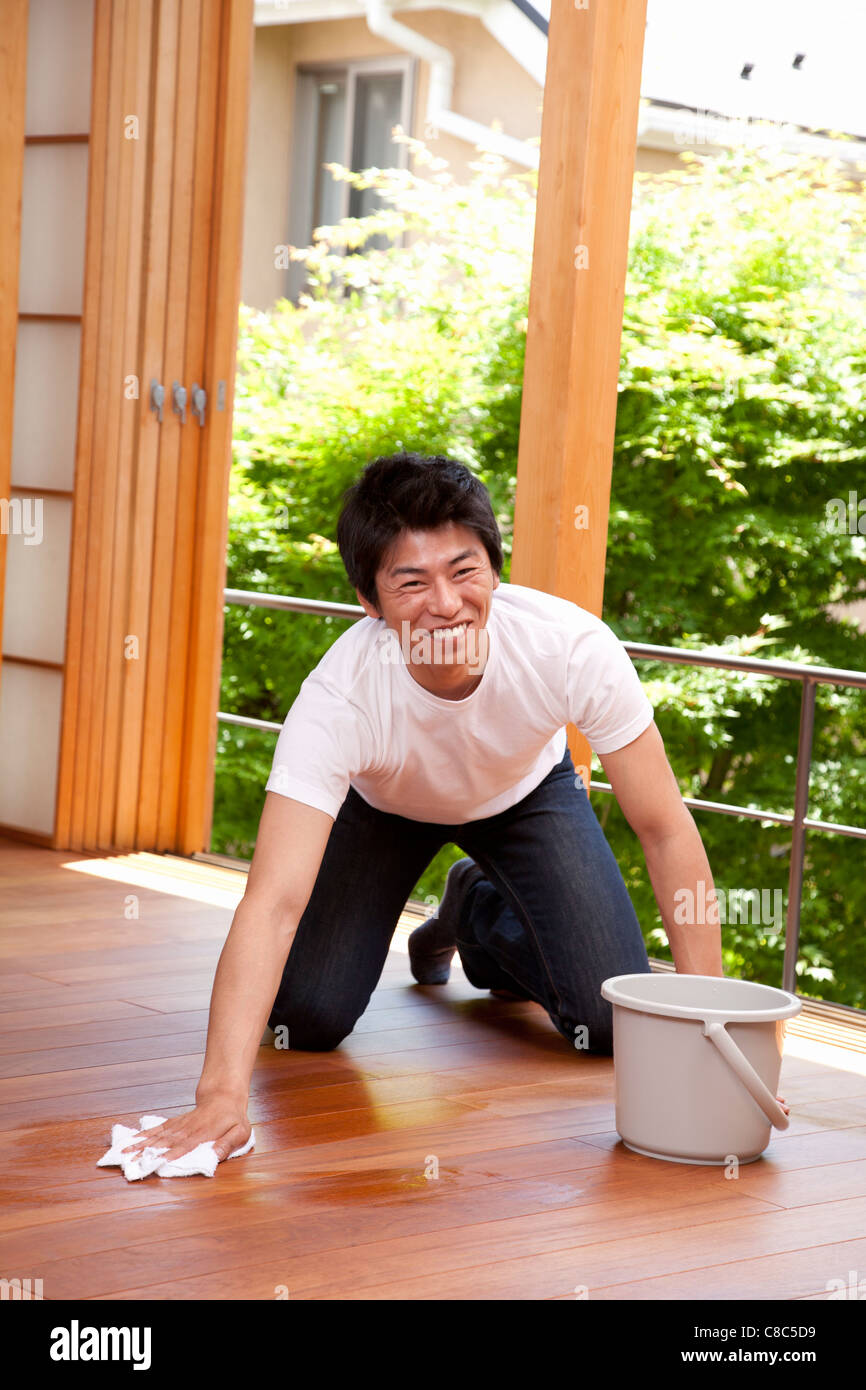 Mid adult man on hands and knees swabbing floor with dust cloth Stock ...