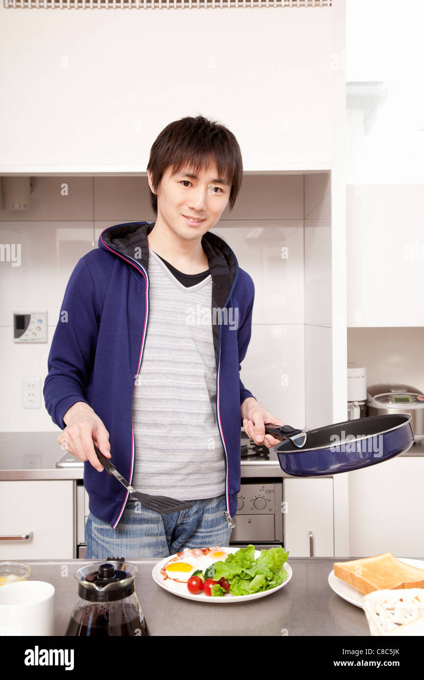 Young man cooking breakfast Stock Photo - Alamy