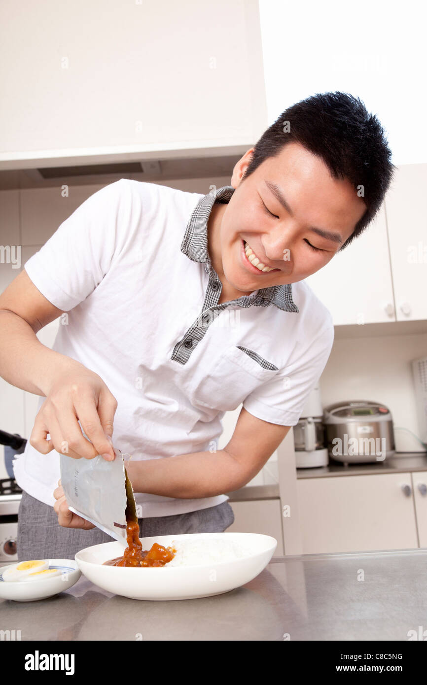 Young man pouring curry sauce from retort pouch to plate Stock Photo ...