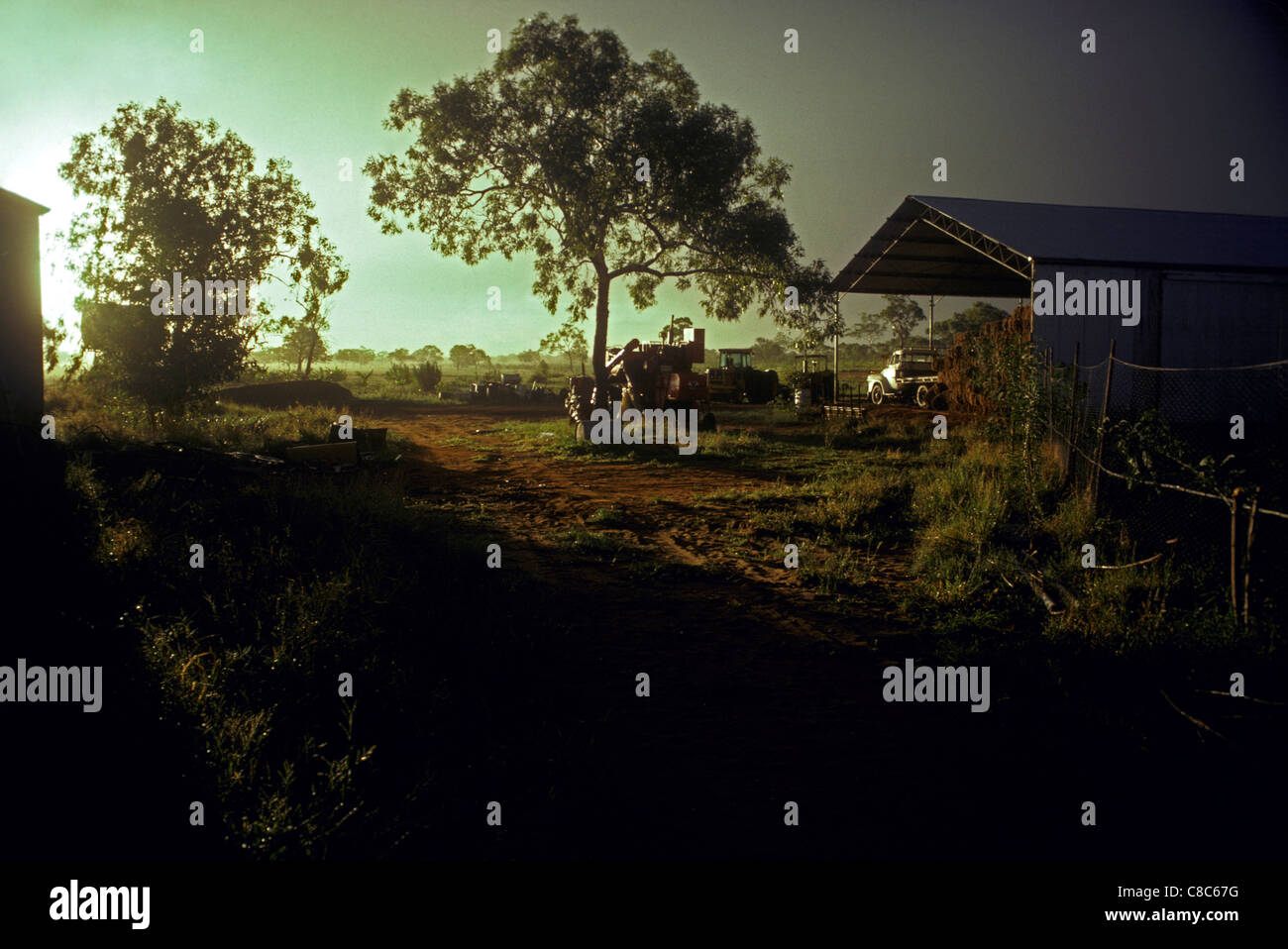 Farmyard scene with farm implements and barn in the late afternoon sun ...