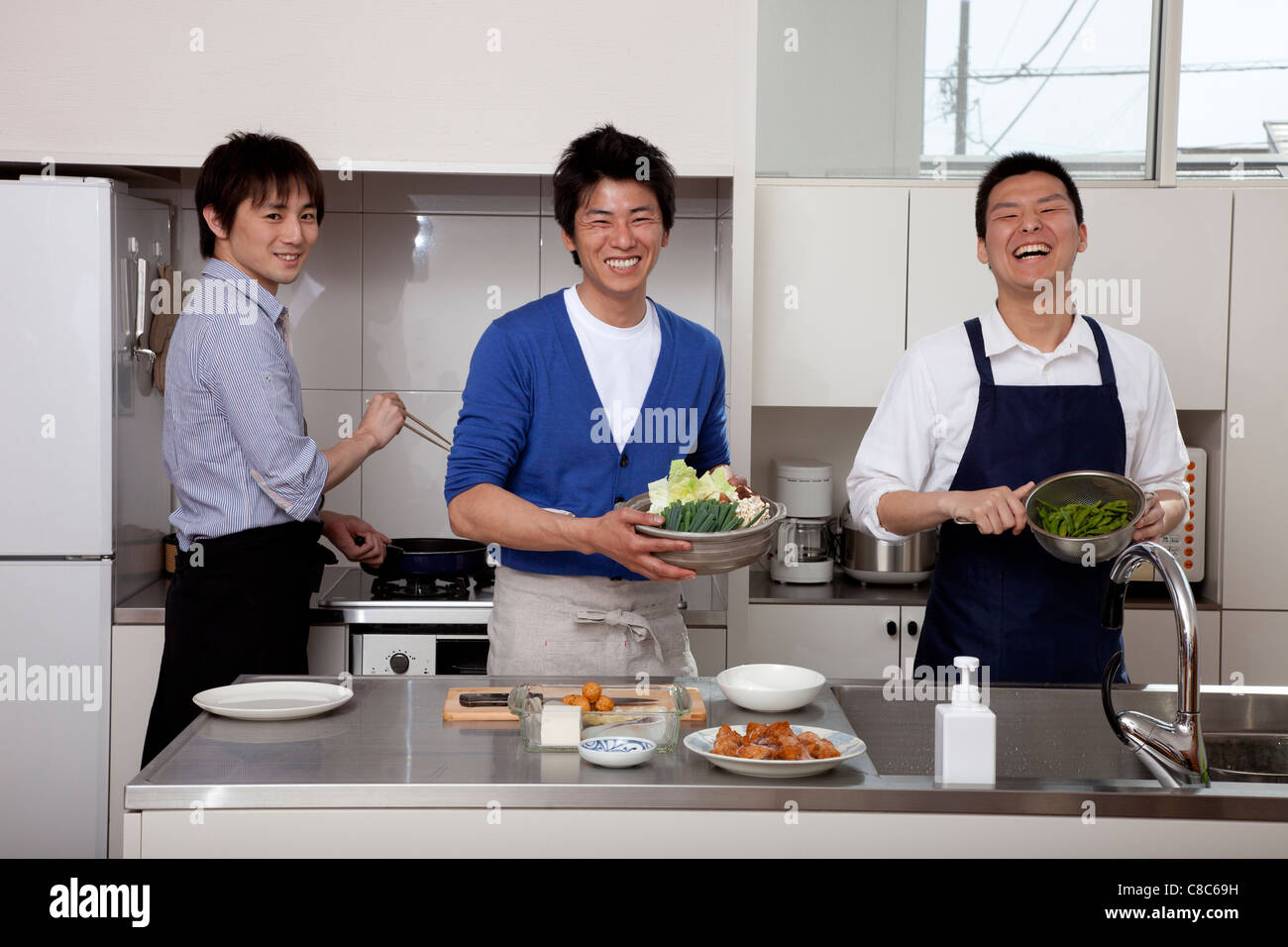 Three men cooking together in the kitchen Stock Photo - Alamy