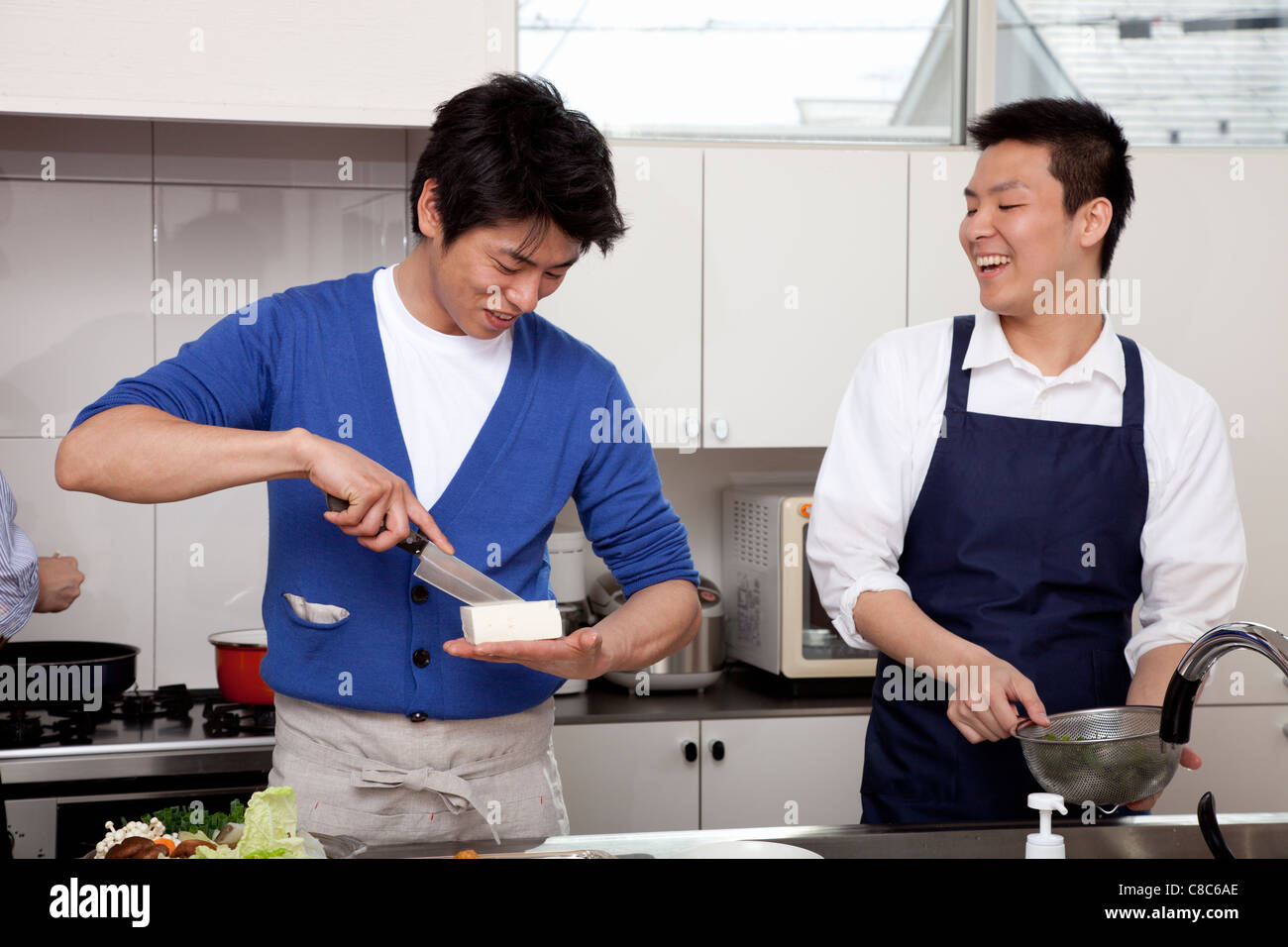 Two men cooking together in the kitchen Stock Photo - Alamy