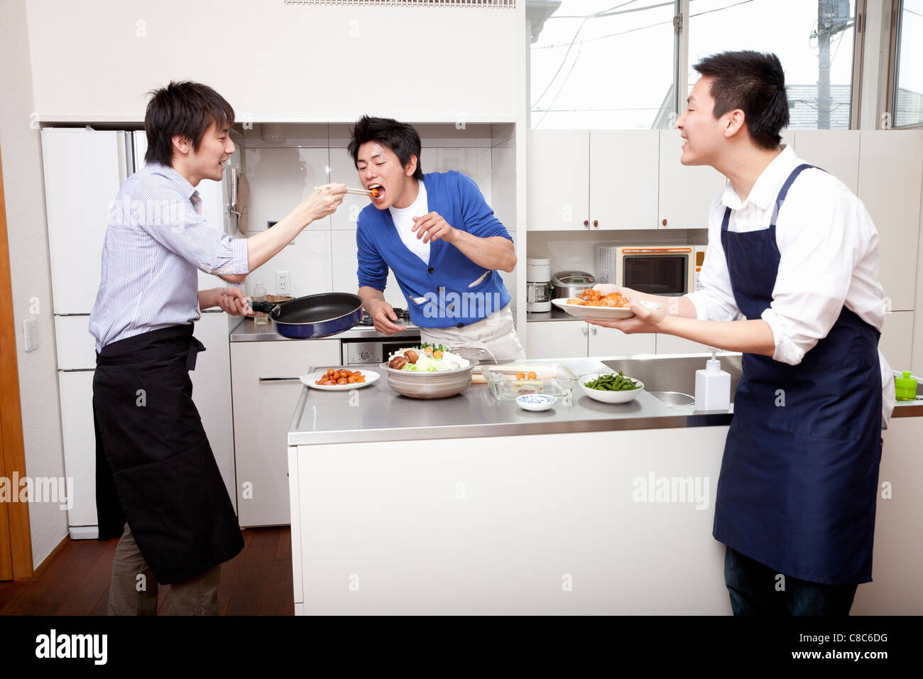 Three men cooking together in the kitchen Stock Photo - Alamy