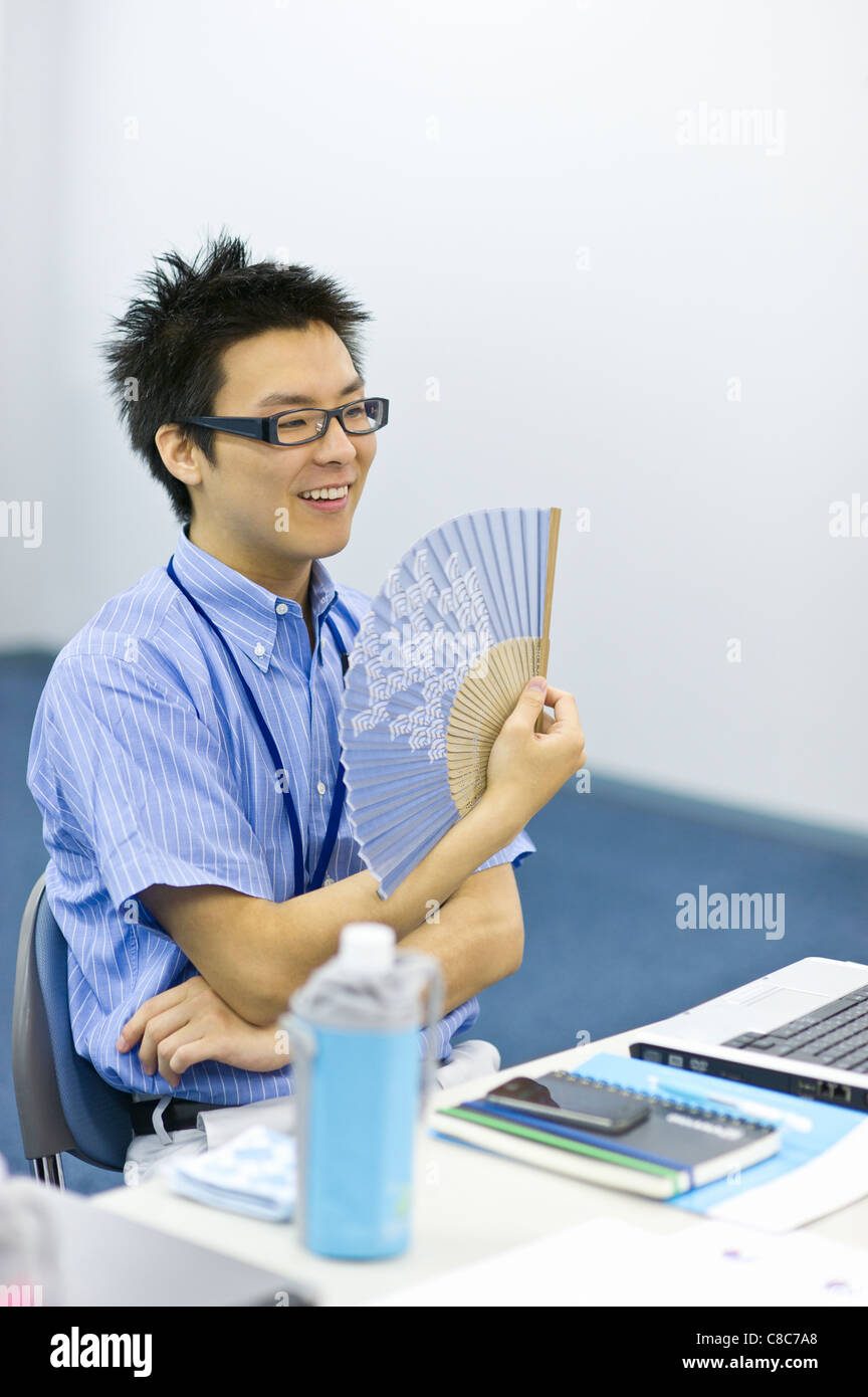 Young businessman holding fan at desk Stock Photo - Alamy