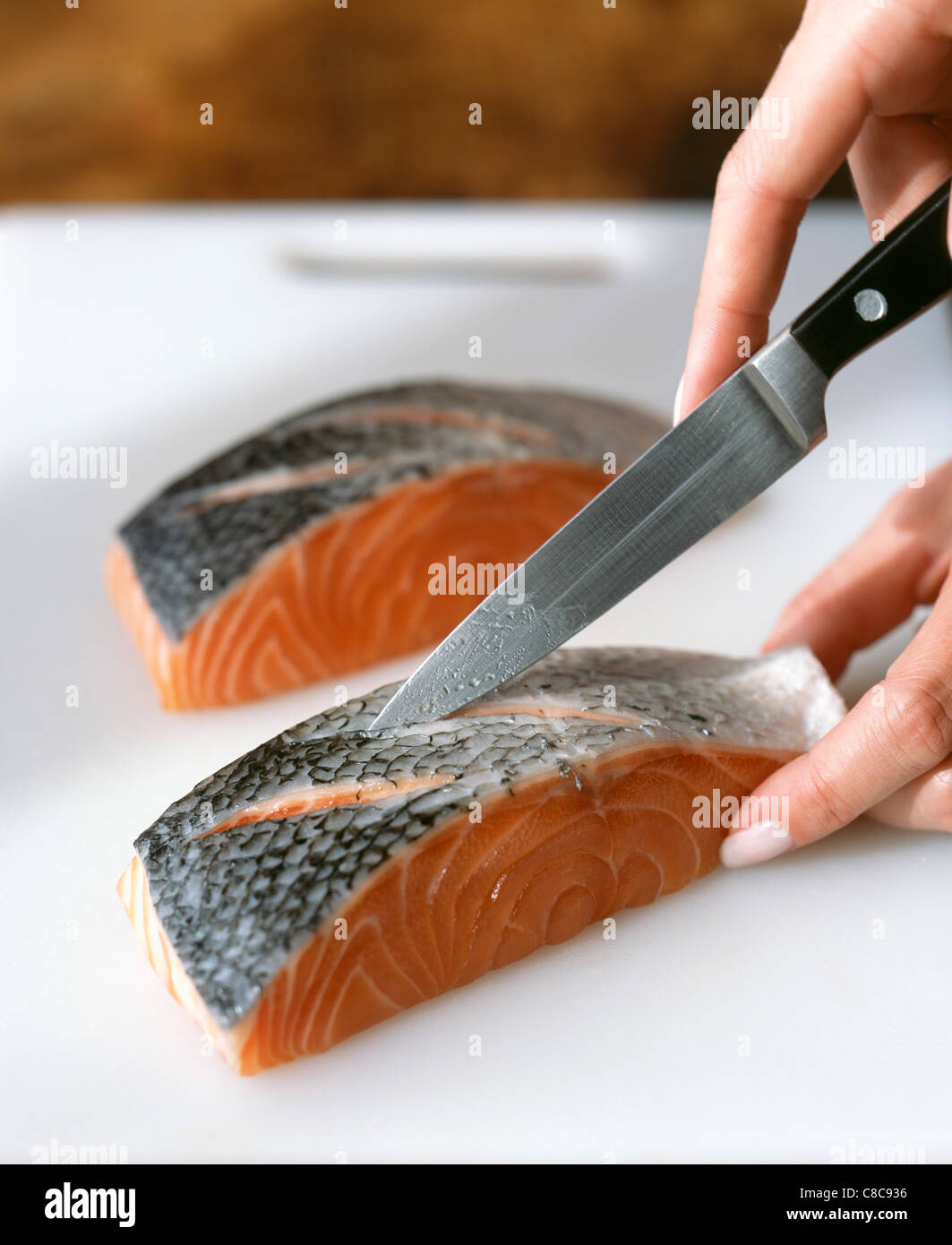 making cuts on the skin side of a piece of salmon before cooking Stock ...