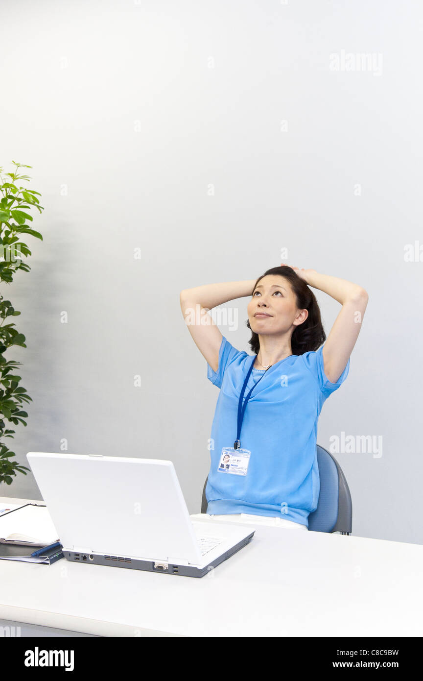Mid adult woman in business casual looking up at desk Stock Photo - Alamy