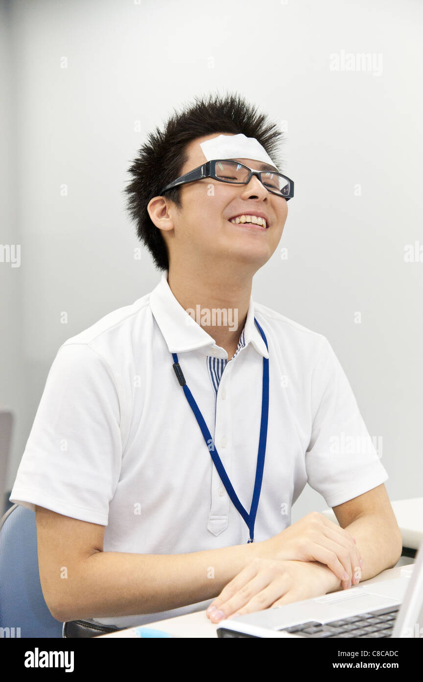 Young man feeling good by cooling gel sheet on forehead Stock Photo - Alamy