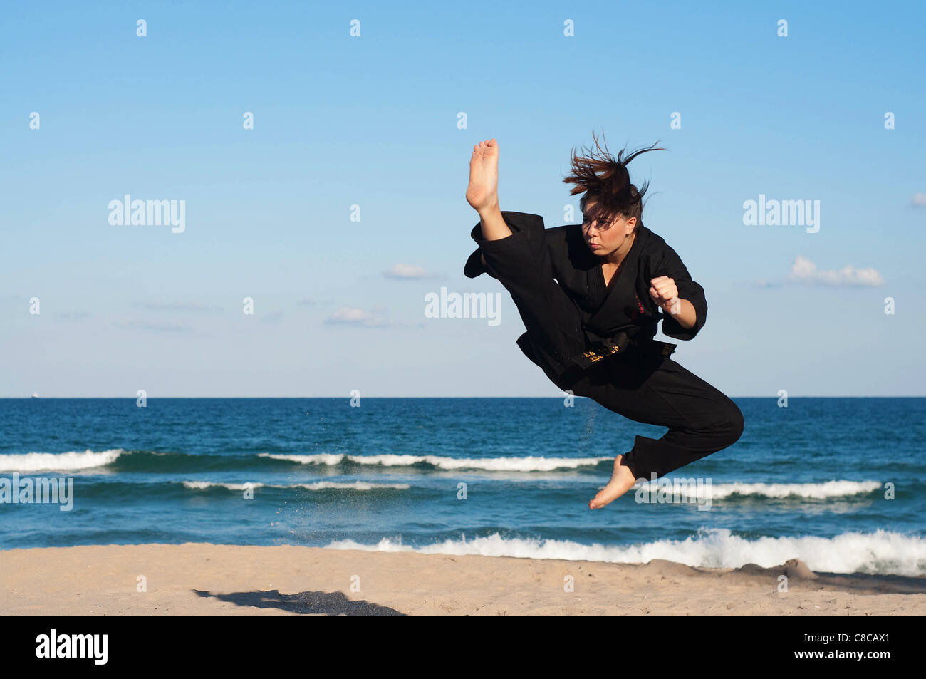 A female, fourth degree, Taekwondo black belt athlete performs a midair ...