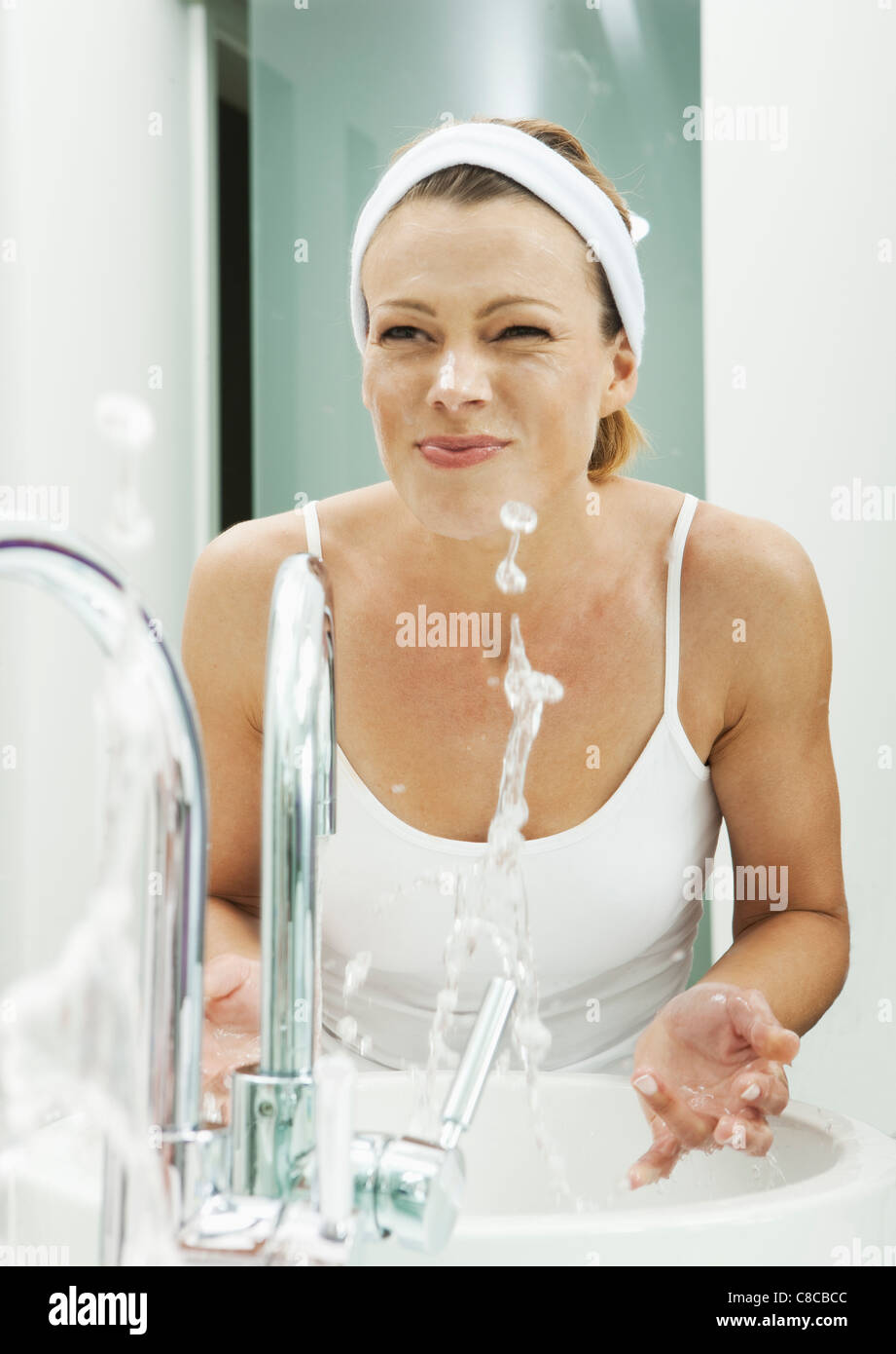 Woman washing her face in bathroom Stock Photo - Alamy