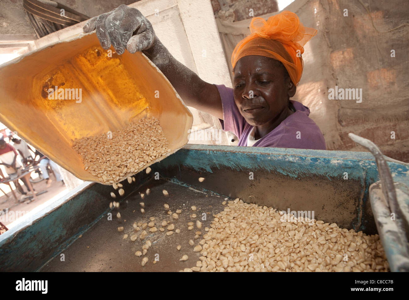 A woman pours maize kernals into a grinder at a mill in Luanshya ...