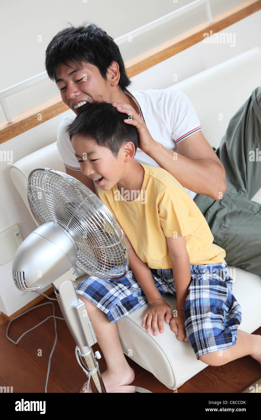 Father and son playing in front of electric fan Stock Photo - Alamy