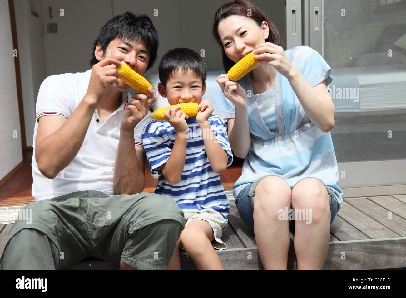 Family eating corn at verandah Stock Photo - Alamy