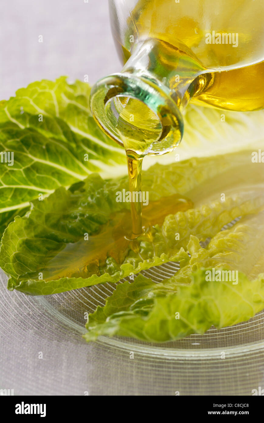 Pouring olive oil onto lettuce leaves Stock Photo - Alamy