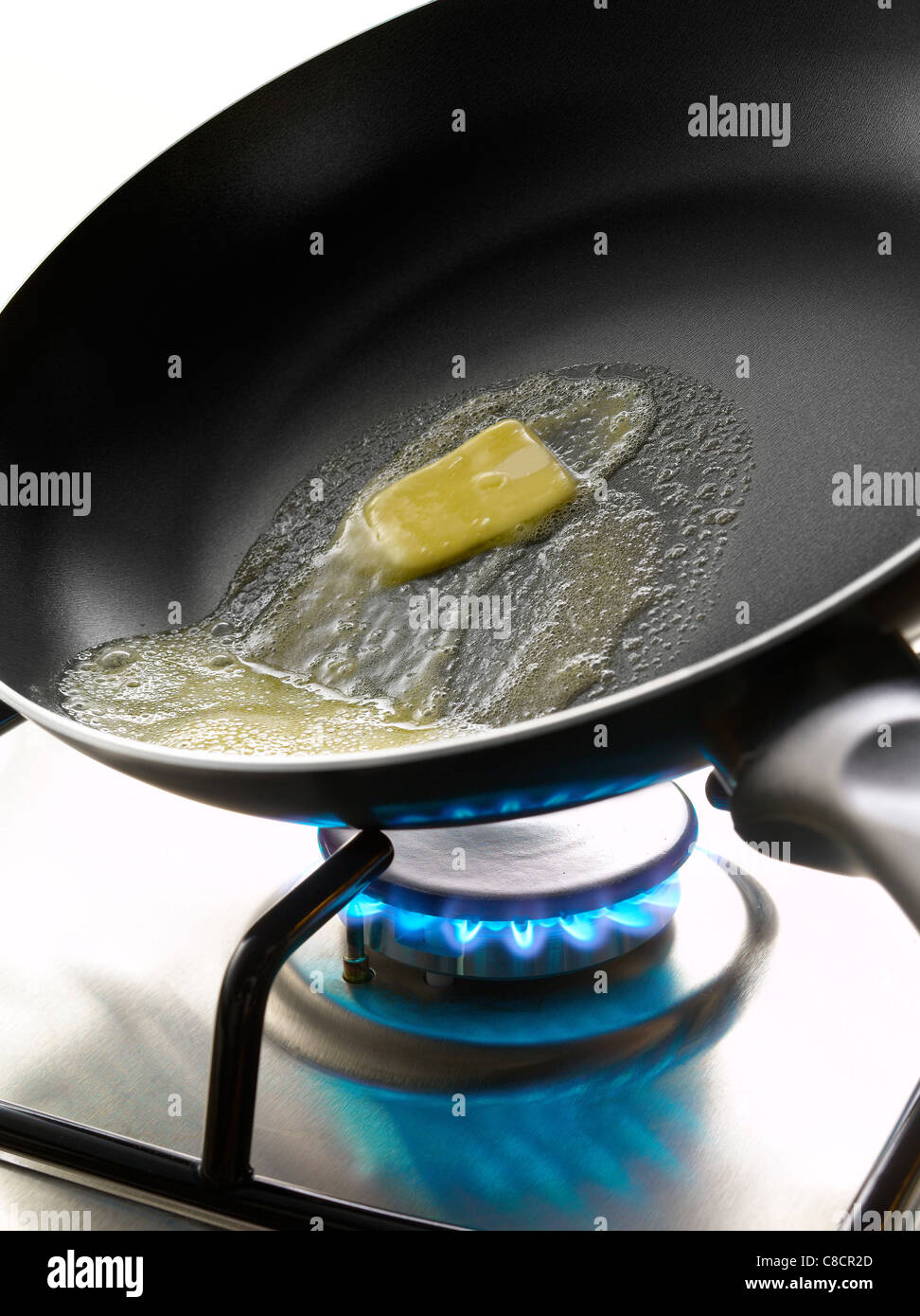 Piece of butter melting in a frying pan on a gas cooker Stock Photo - Alamy