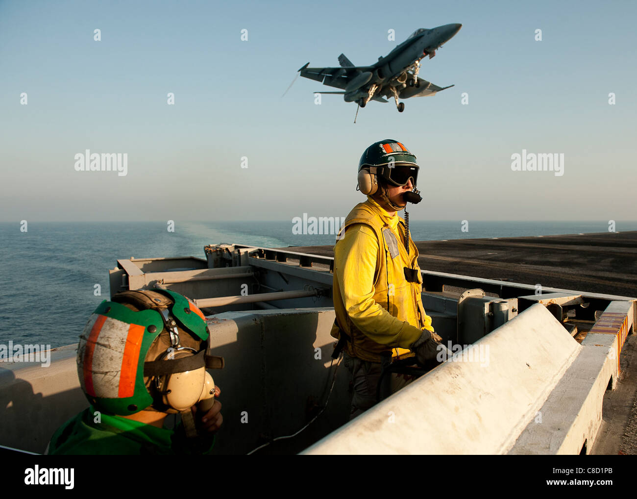 the arresting gear officer as an F/A-18C Hornet (VFA) 192 lands aboard ...