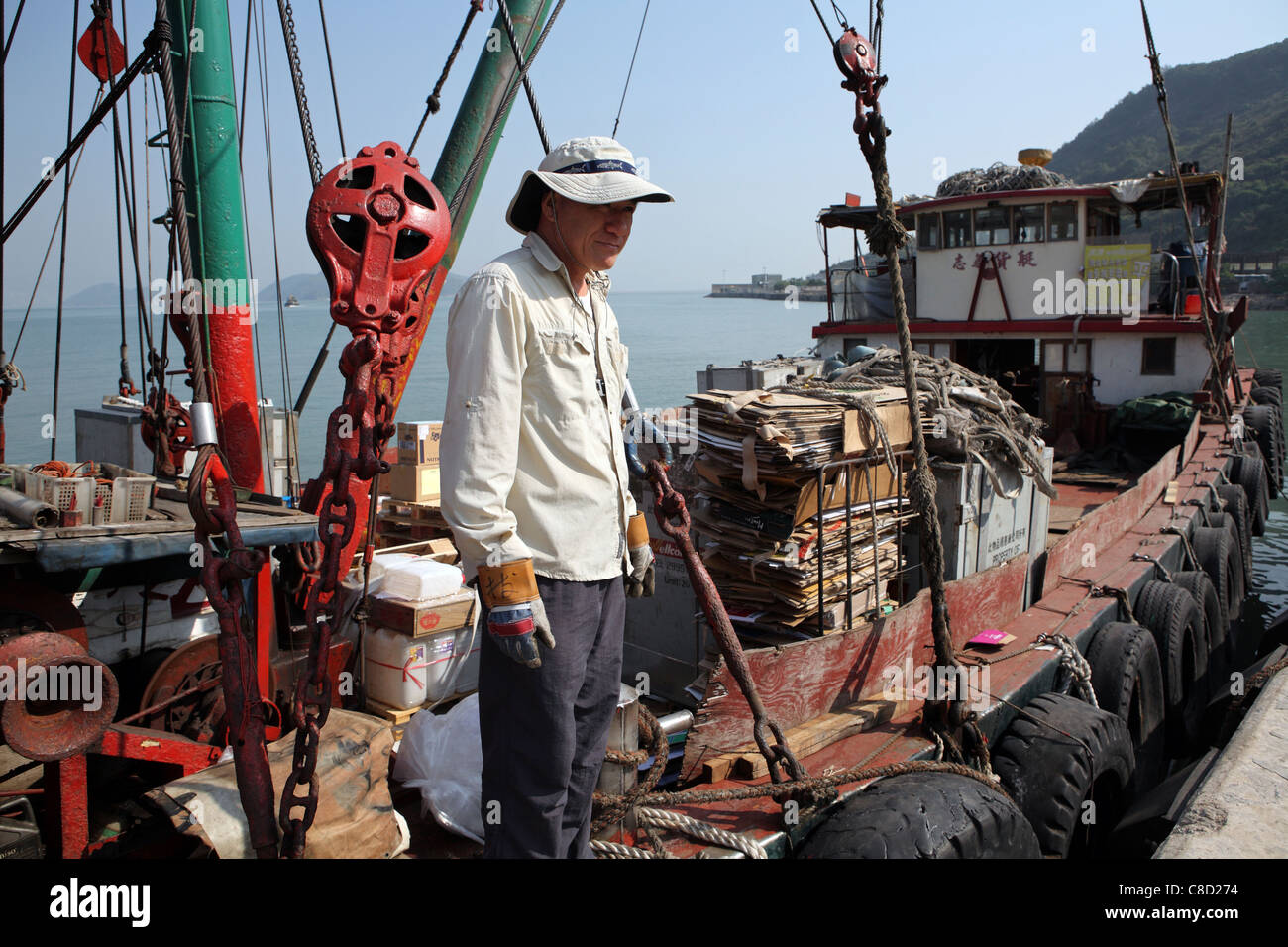 Man loading ship with bales of paper & card for recycling, dock at ...