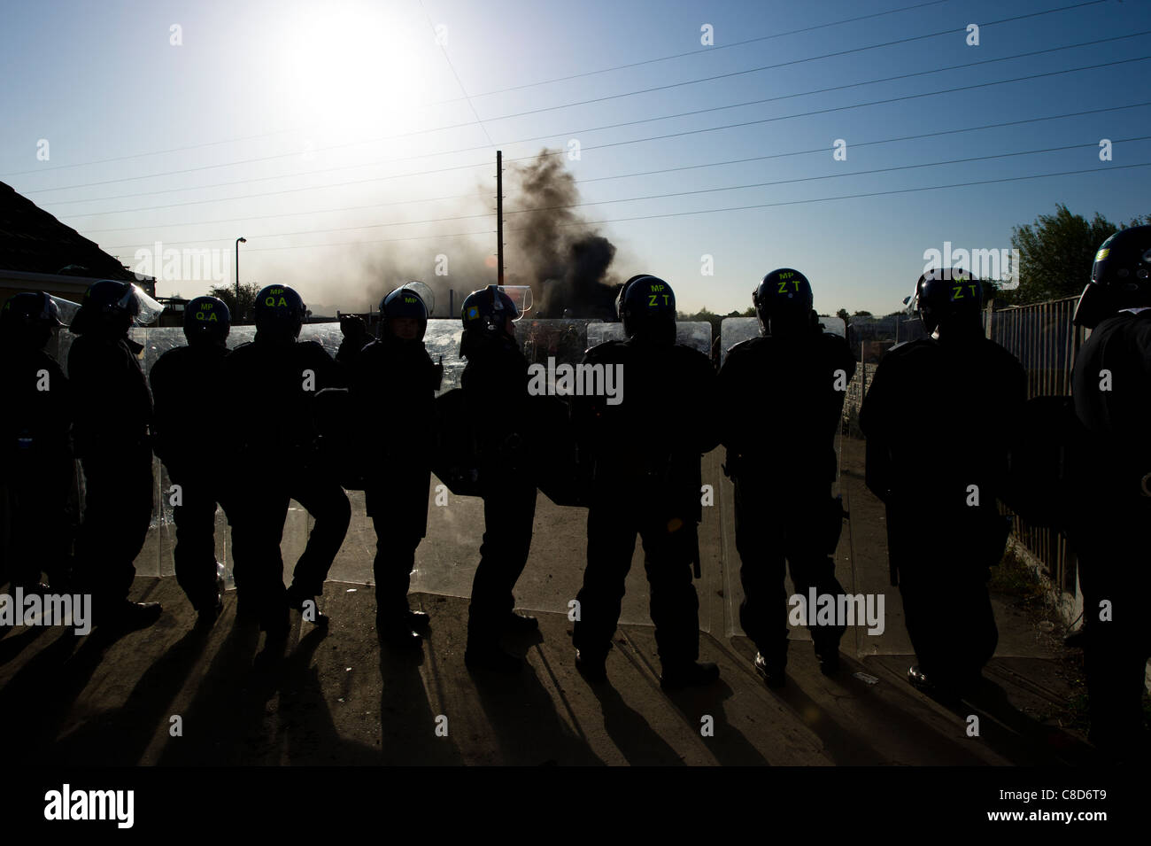 A line of riot police officers with their shields forming a cordon ...