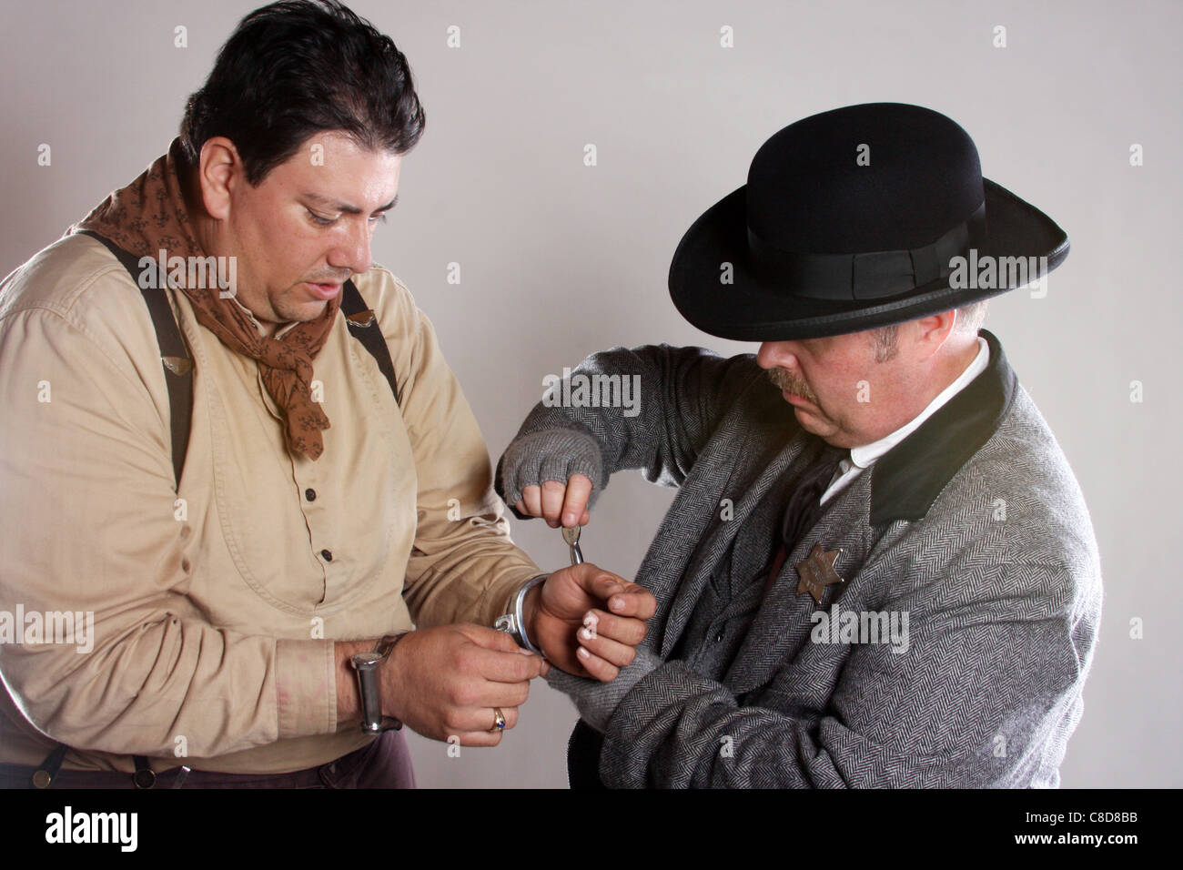 A sheriff putting handcuffs on a cowboy Stock Photo - Alamy