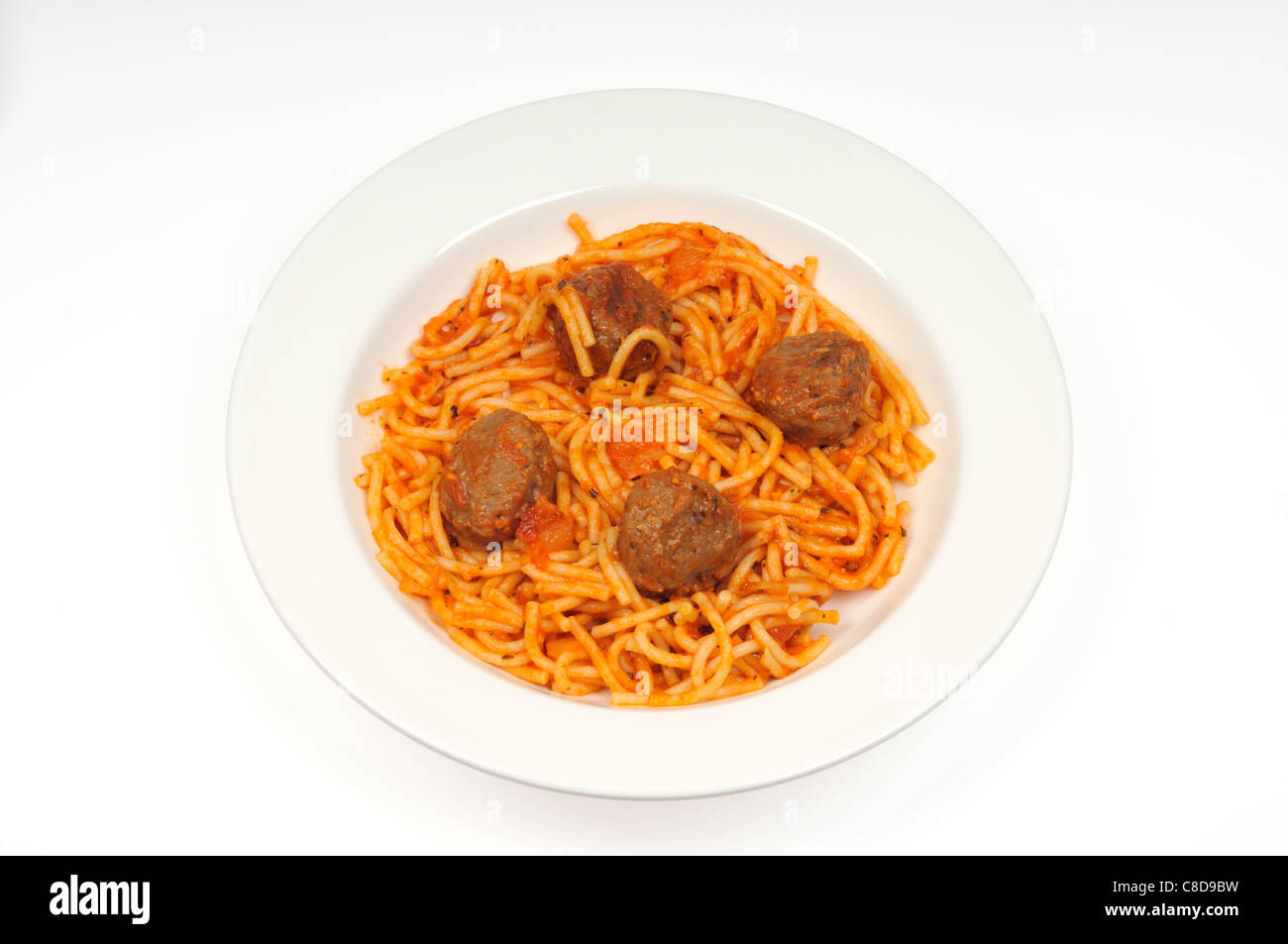 A serving of spaghetti and meatballs in a white ball on white ...