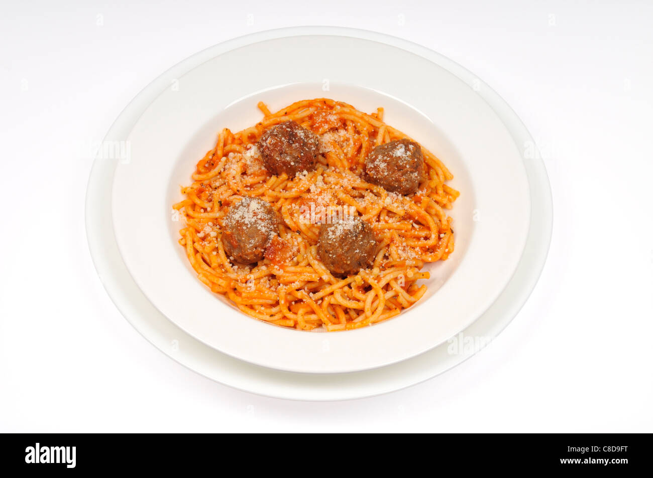 A serving of spaghetti and meatballs topped with cheese in a white bowl ...