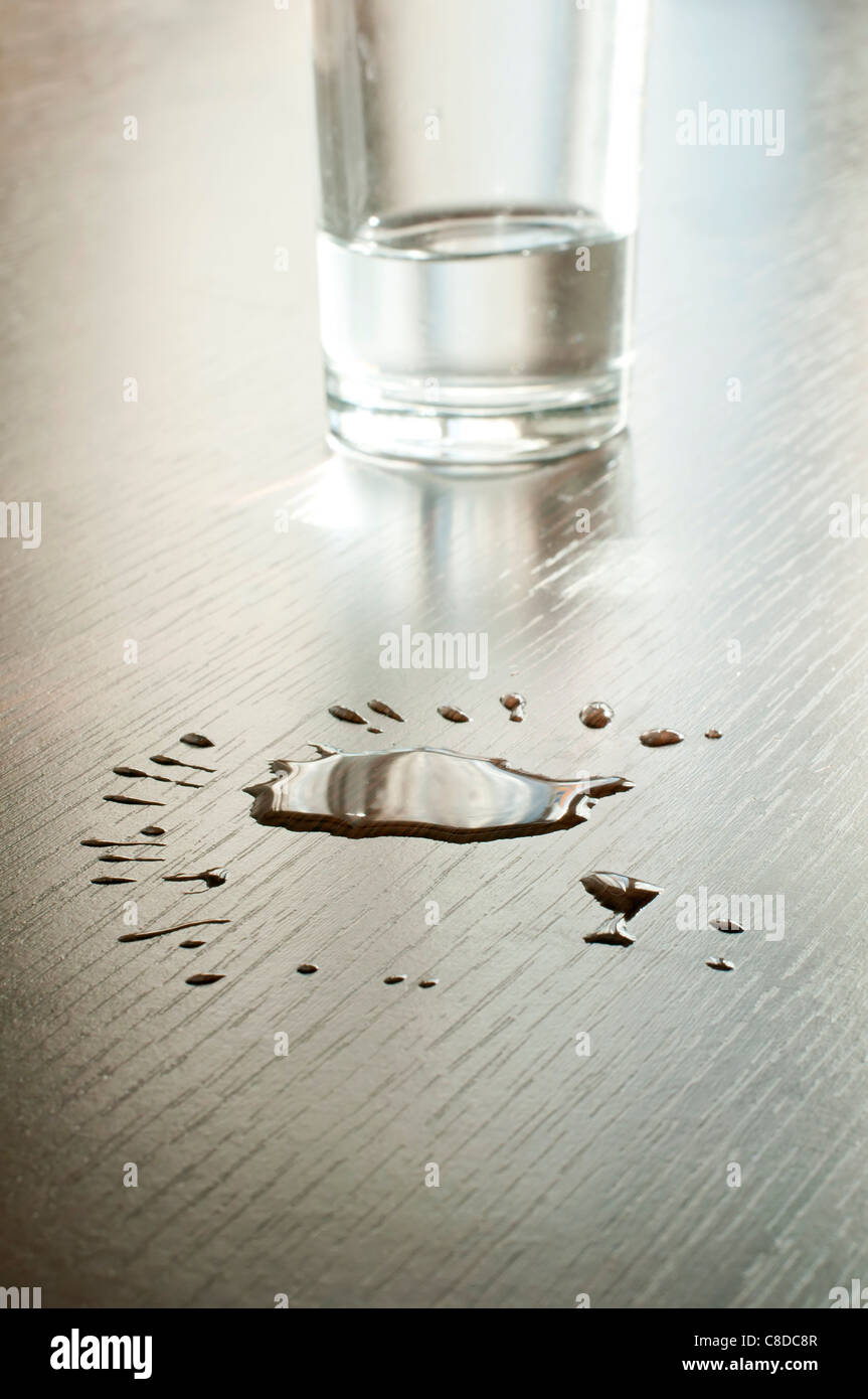 Spilled water on a table. Cup and droplets around Stock Photo - Alamy