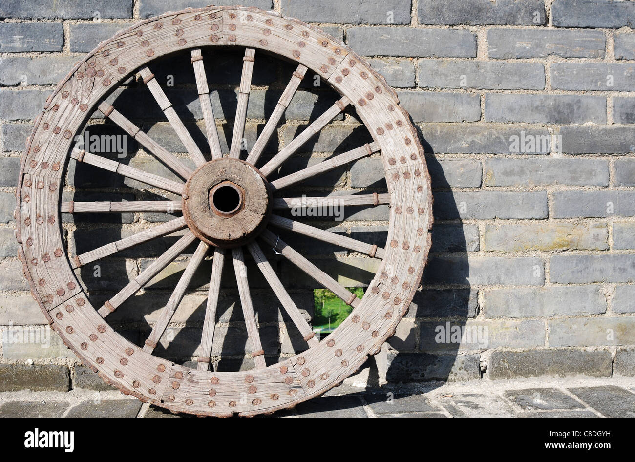 Old carriage wheel against brick wall Stock Photo - Alamy