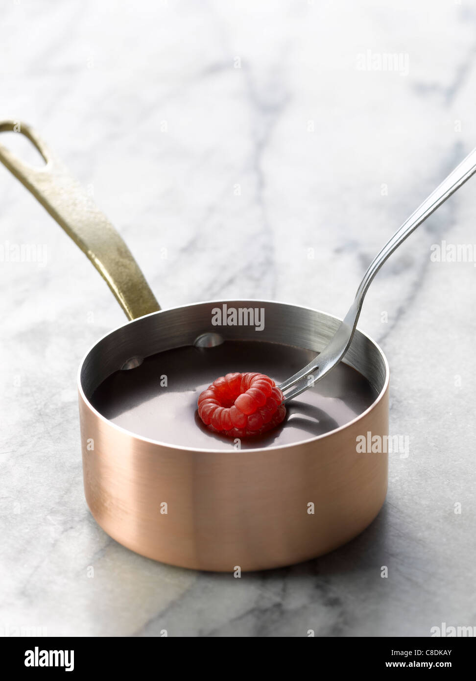 Dipping a raspberry into a saucepan of melted chocolate Stock Photo - Alamy