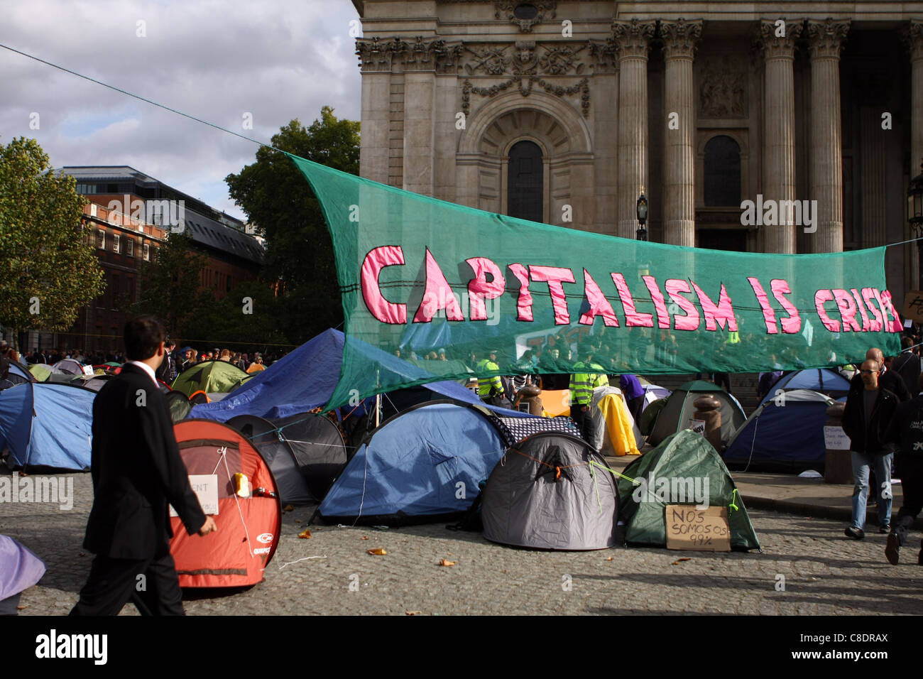 A businessman looking at an anti-capitalist banner at the protest ...