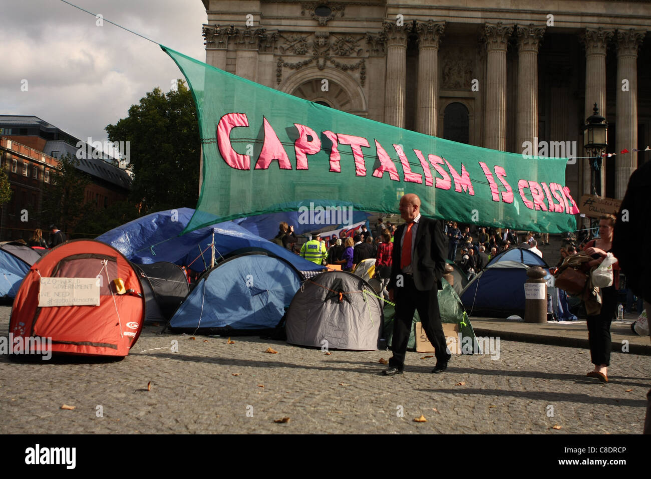 A businessman walking passed an anti-capitalist banner at the protest ...