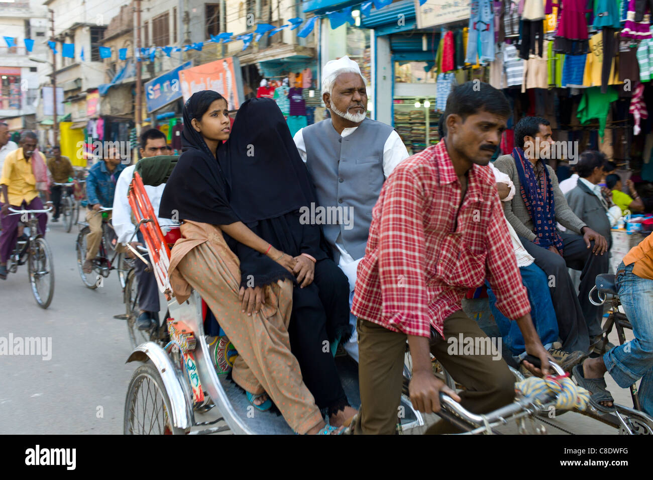 Street scene in holy city of Varanasi, muslim family ride in rickshaw ...