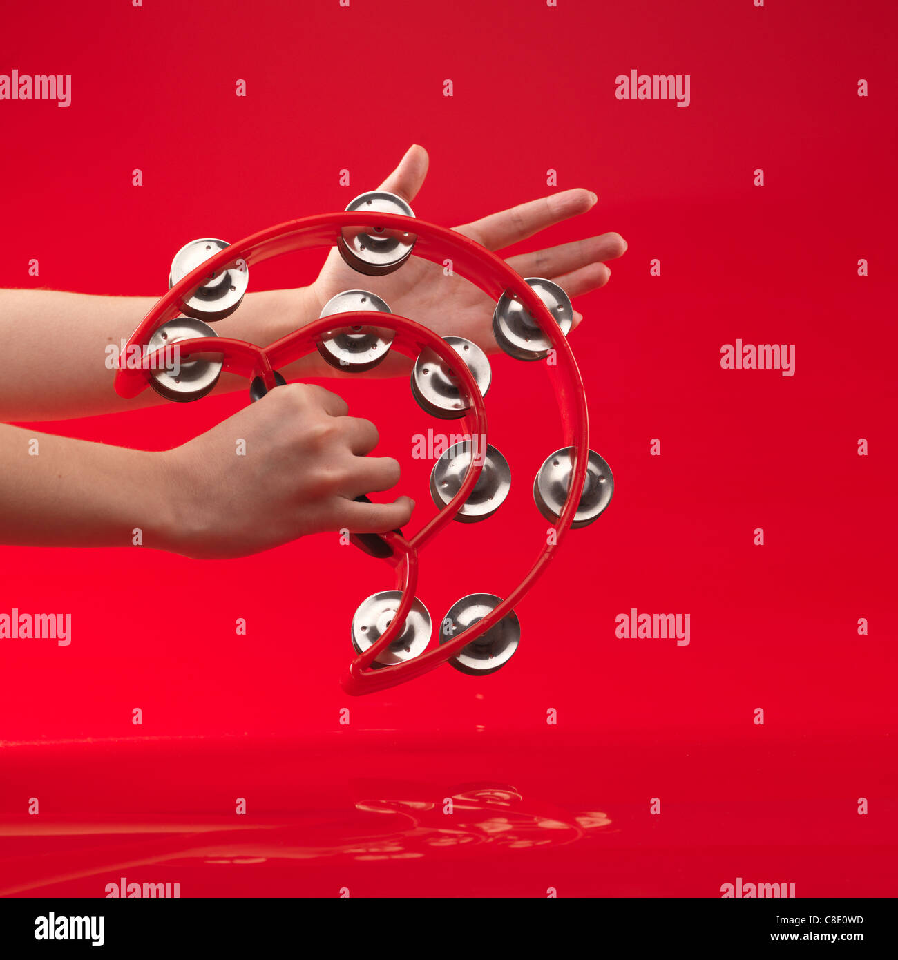 woman's hands holding a tambourine on red background Stock Photo - Alamy