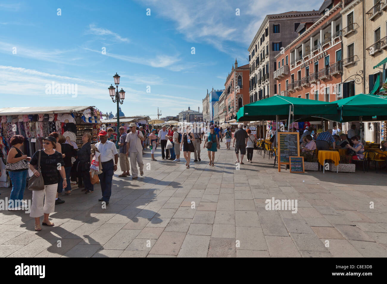 Tourists shopping at market stalls on the grand canal side in Venice near to Saint Marks Square ...