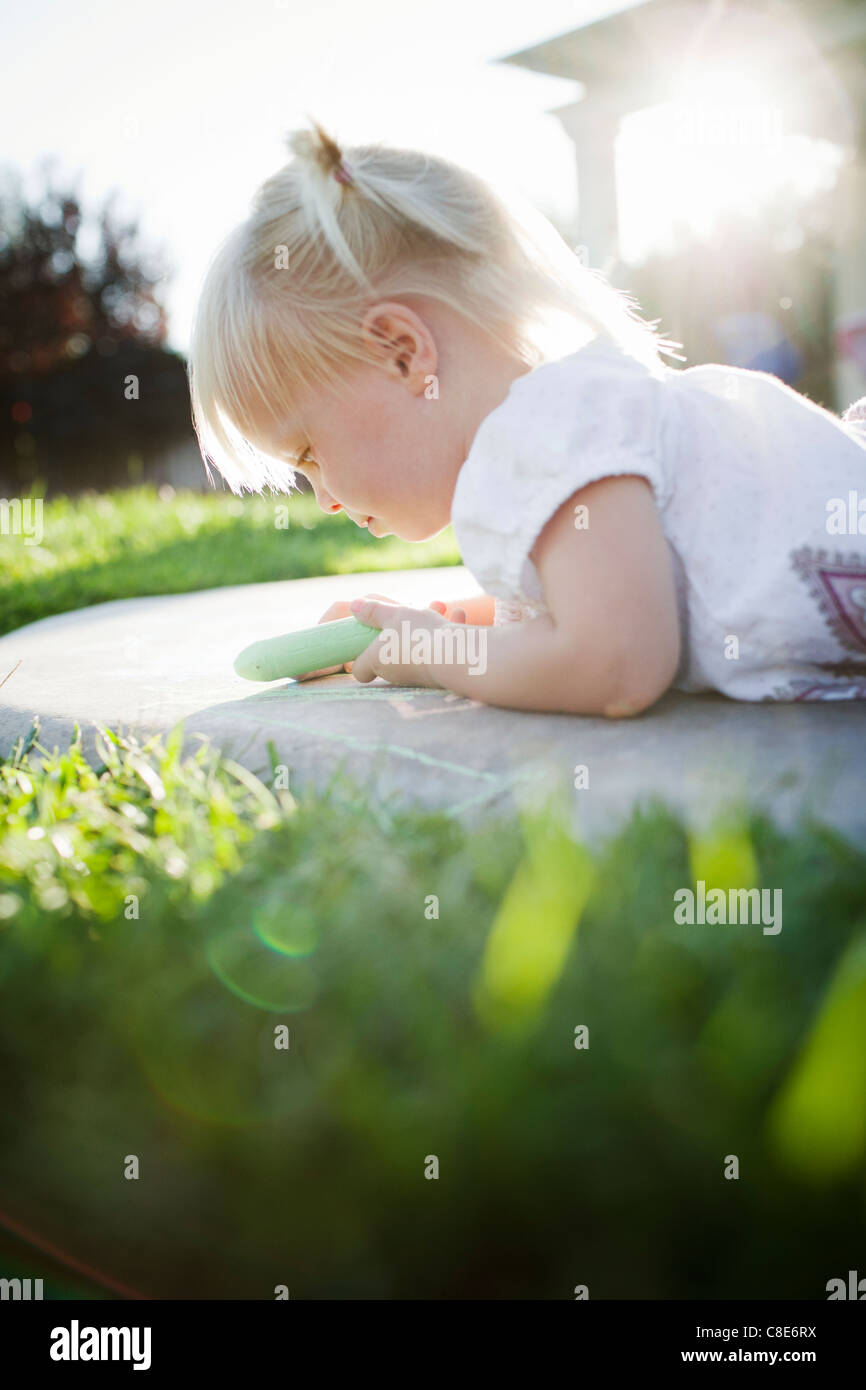 Toddler Girl Laying on Ground Playing with Sidewalk Chalk Stock Photo ...