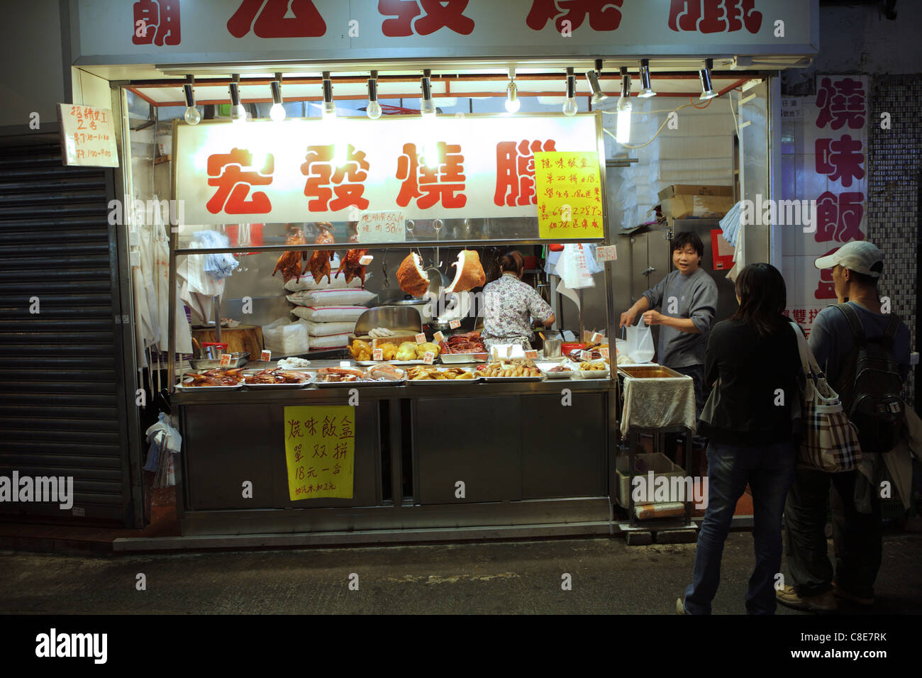 People in front of night time, food stall in market in Hong Kong street ...