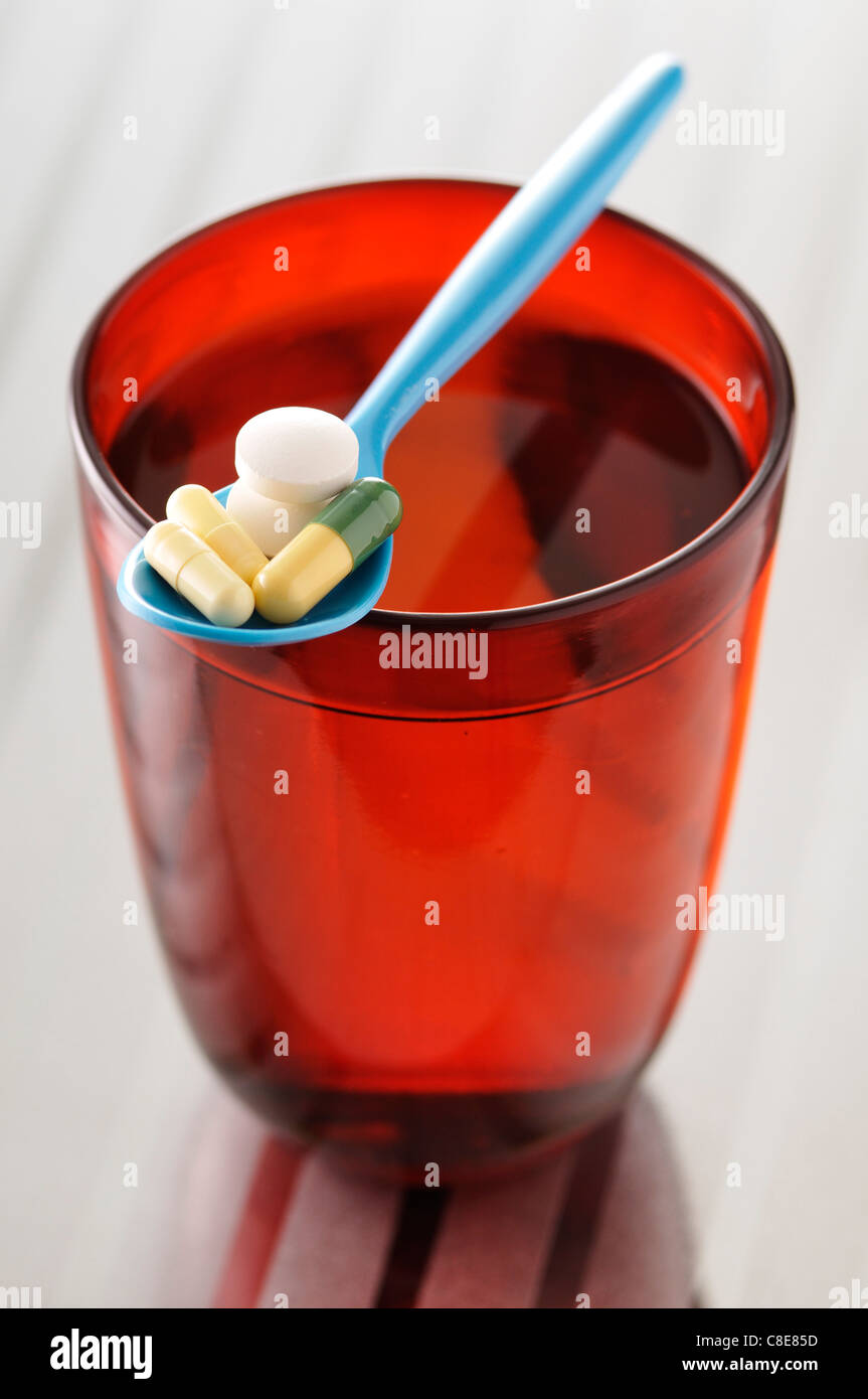 Spoonful of pills and glass of water Stock Photo - Alamy